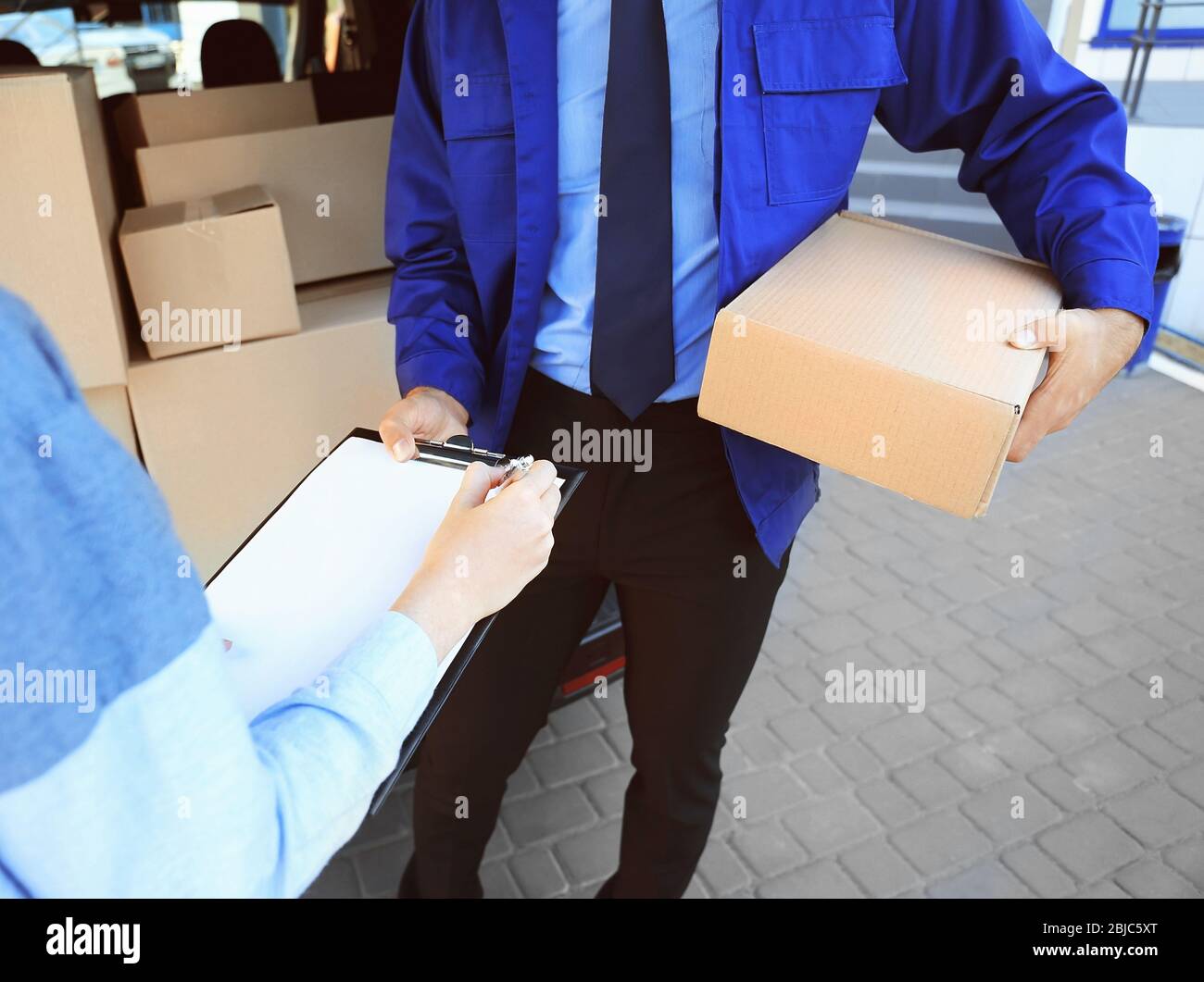Woman receiving parcel from delivery man Stock Photo - Alamy