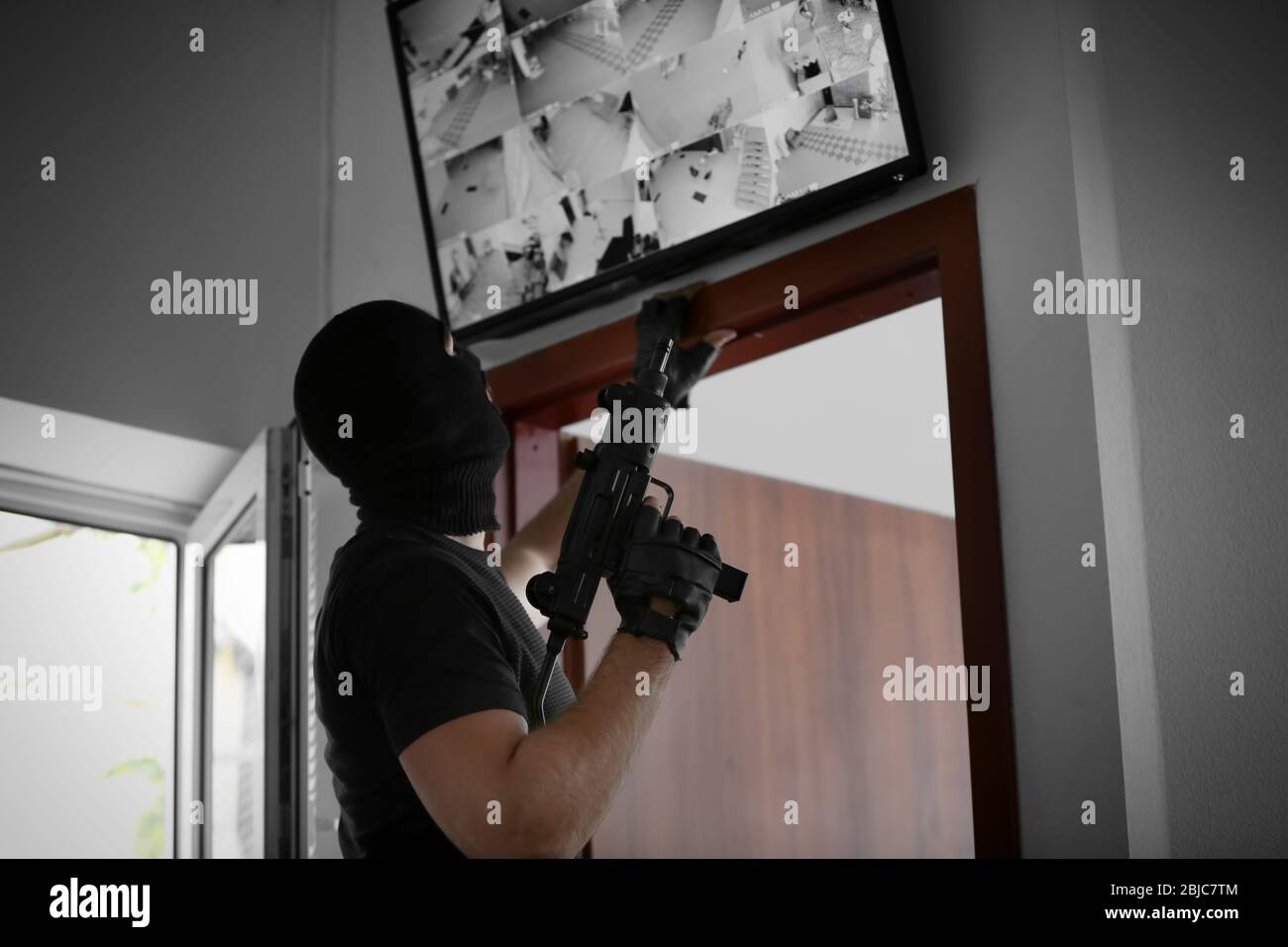 Thief with gun looking at monitor Stock Photo - Alamy