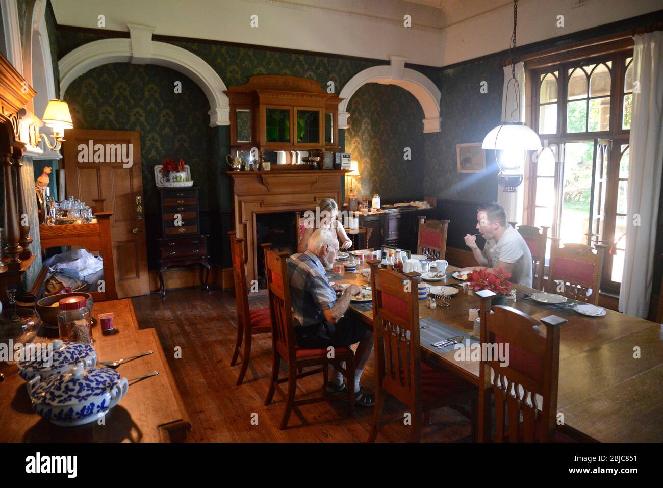 family of three having breakfast in old colonial style sandstone ...