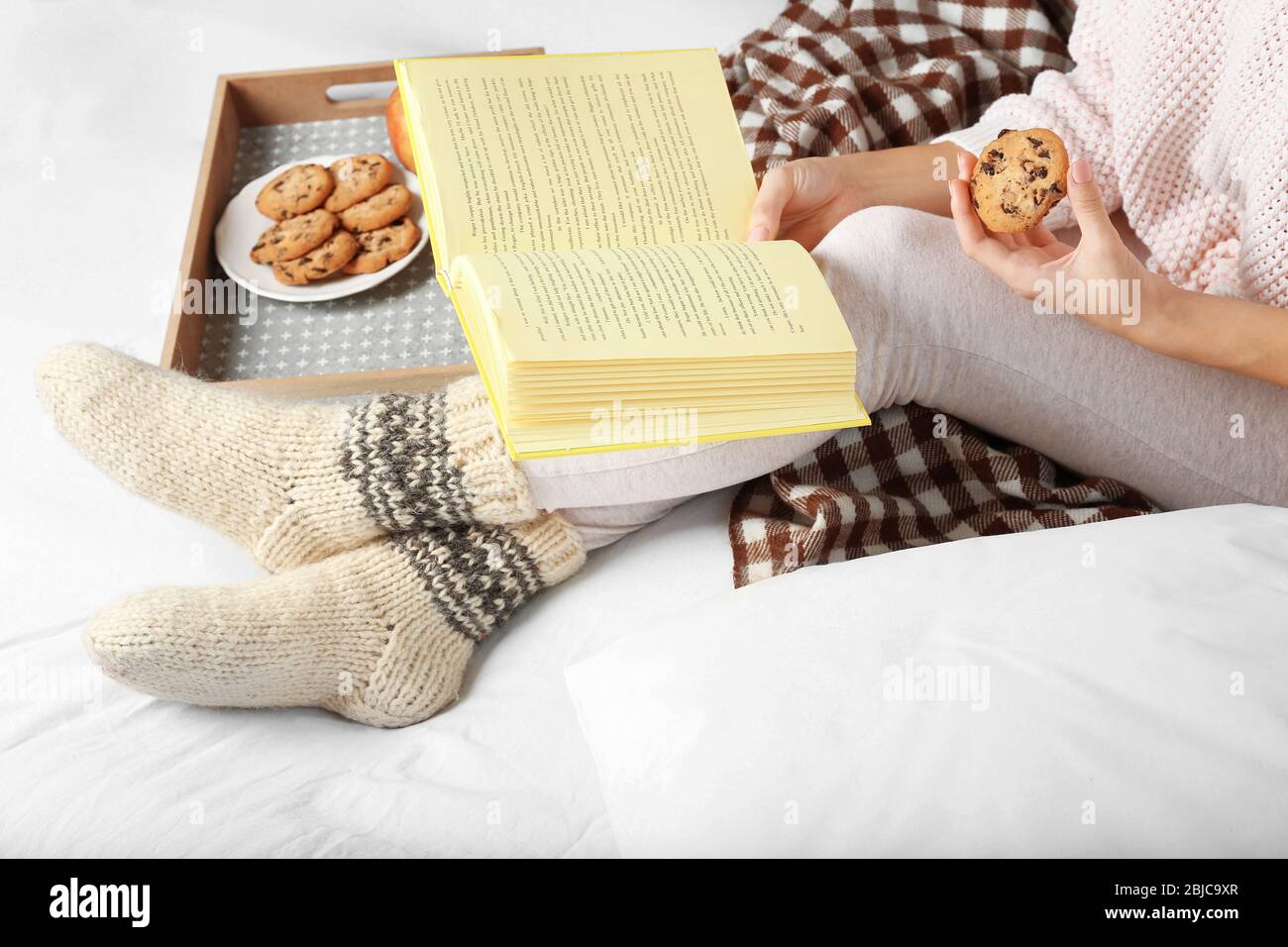 Girl with food reading book on bed Stock Photo - Alamy