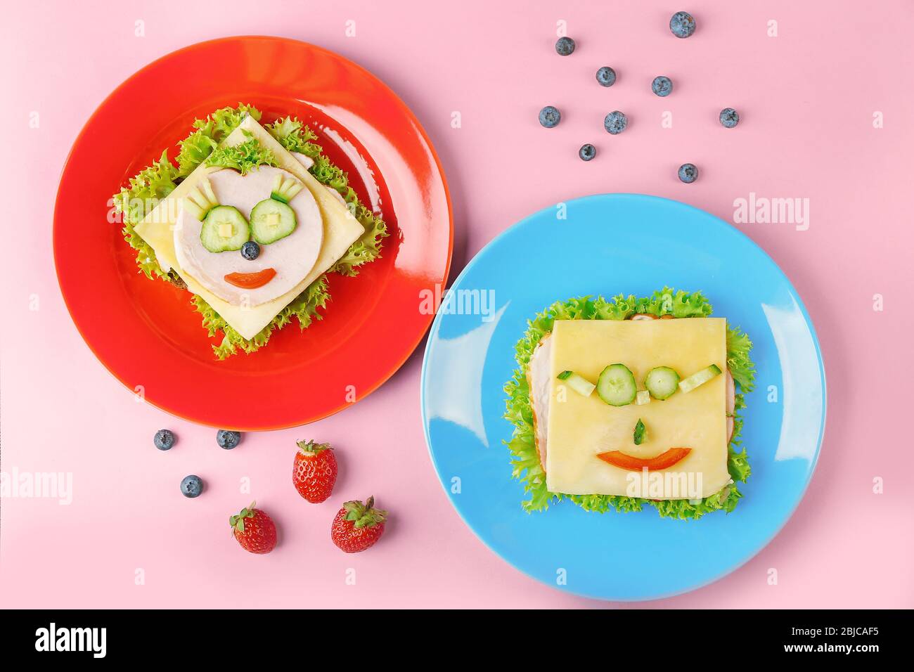 Red and blue plates with funny sandwiches on pink background Stock ...