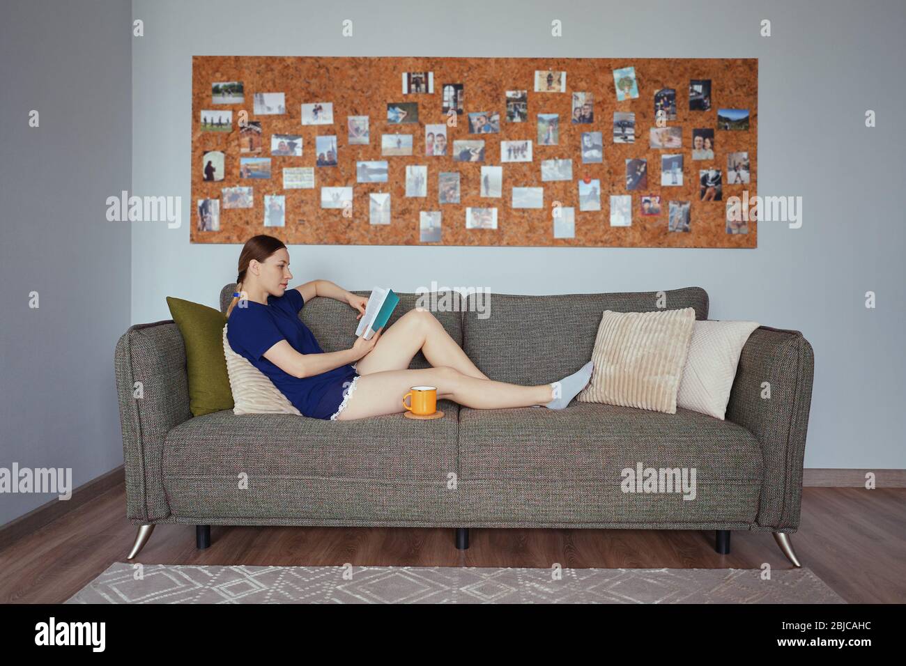 A beautiful Caucasian woman reading a book with a cup of tea while ...