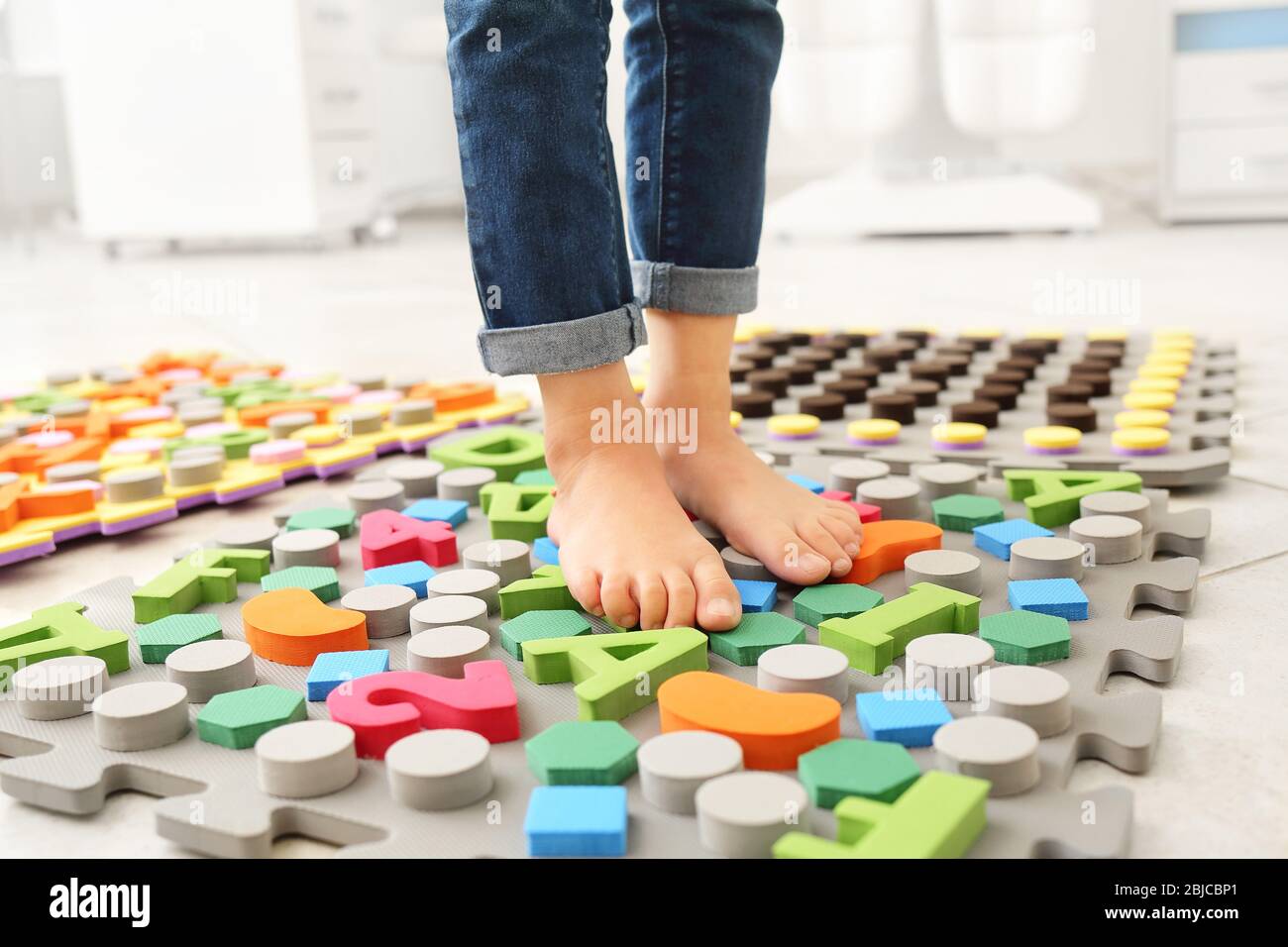 Child flatfoot treatment using special massage carpet.Little girl on ...