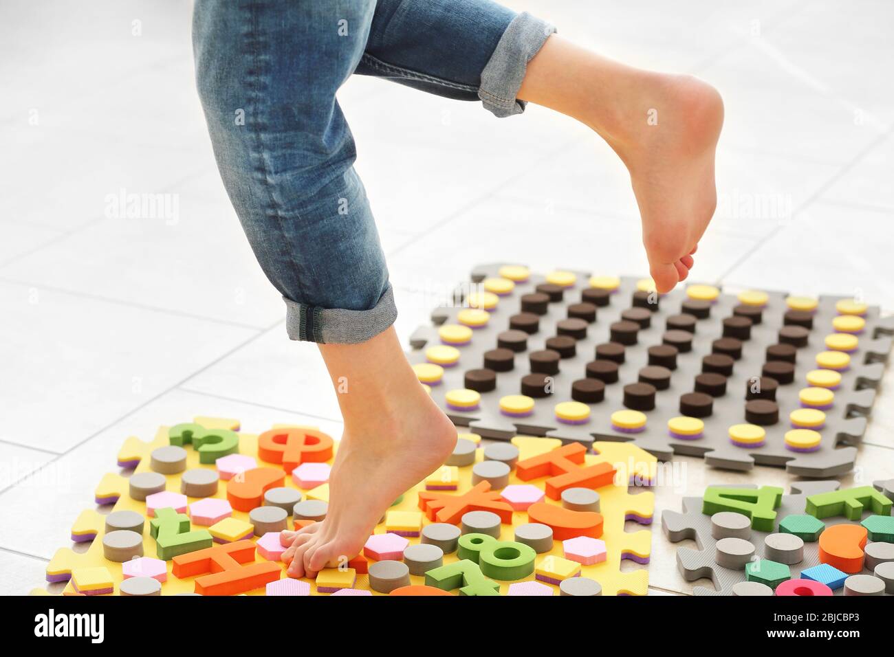 Child flatfoot treatment using special massage carpet.Little girl on ...