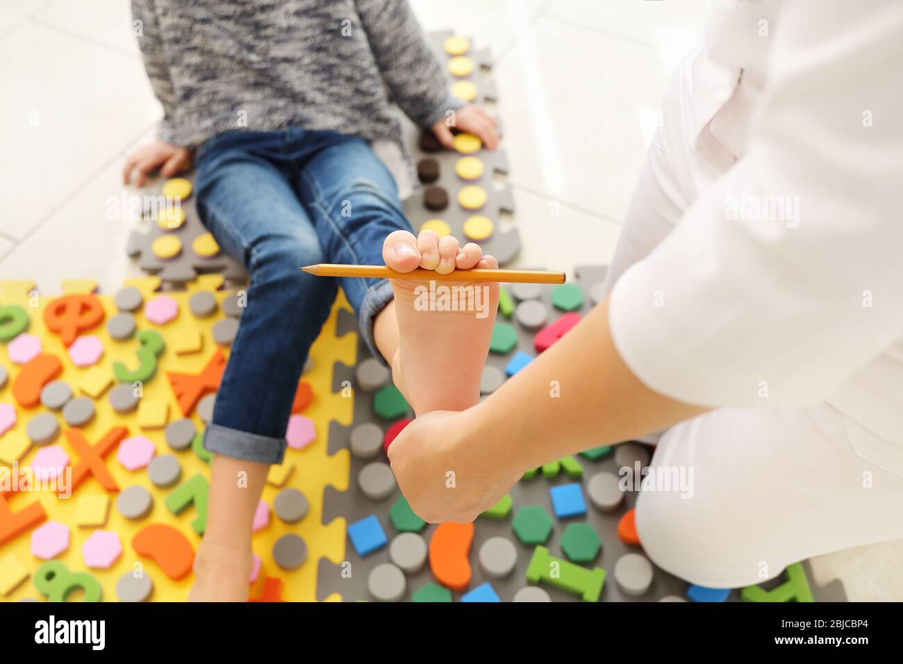 Child flatfoot treatment using special massage carpet.Little girl on ...