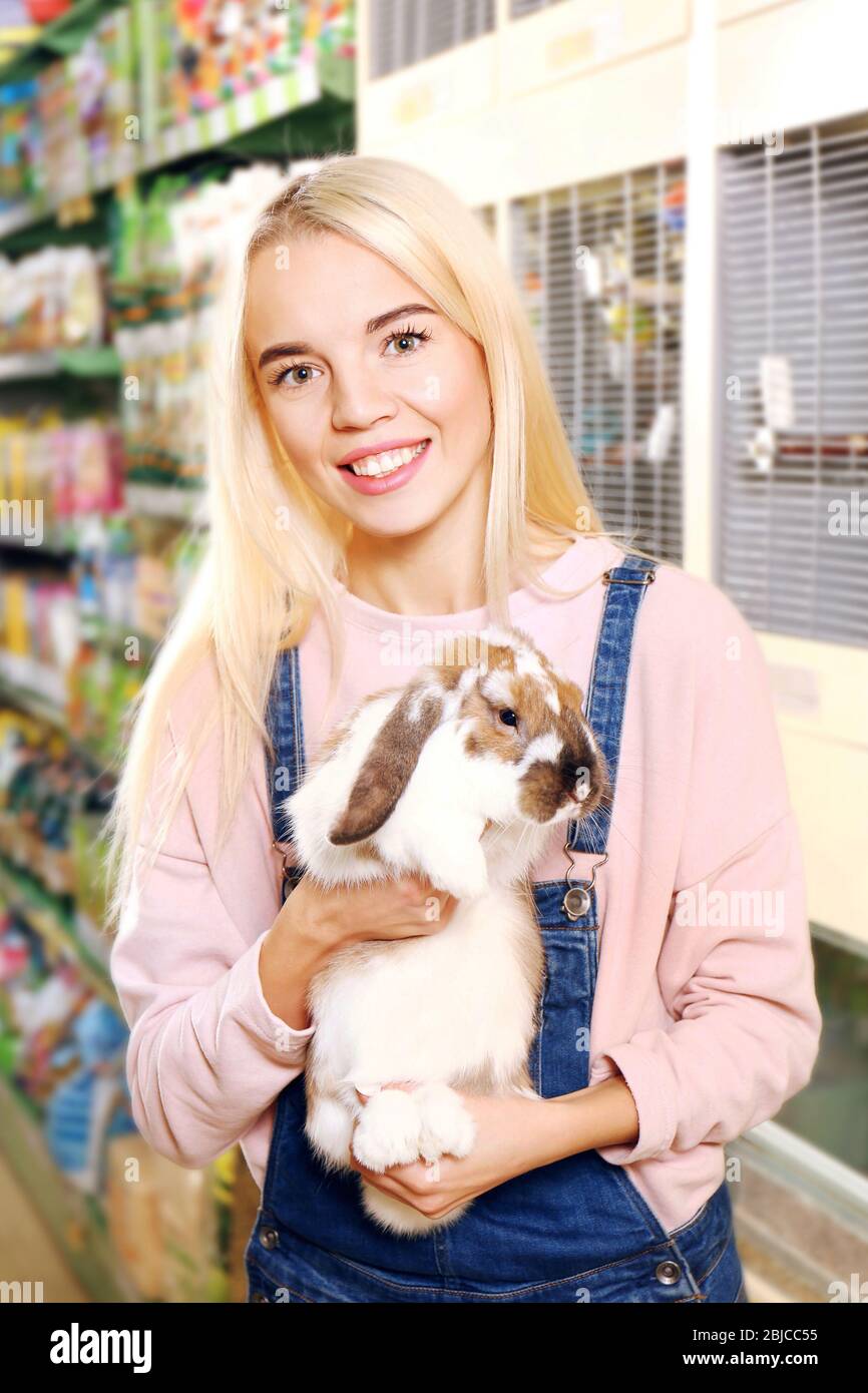 Beautiful young woman holding cute rabbit in pet shop Stock Photo - Alamy