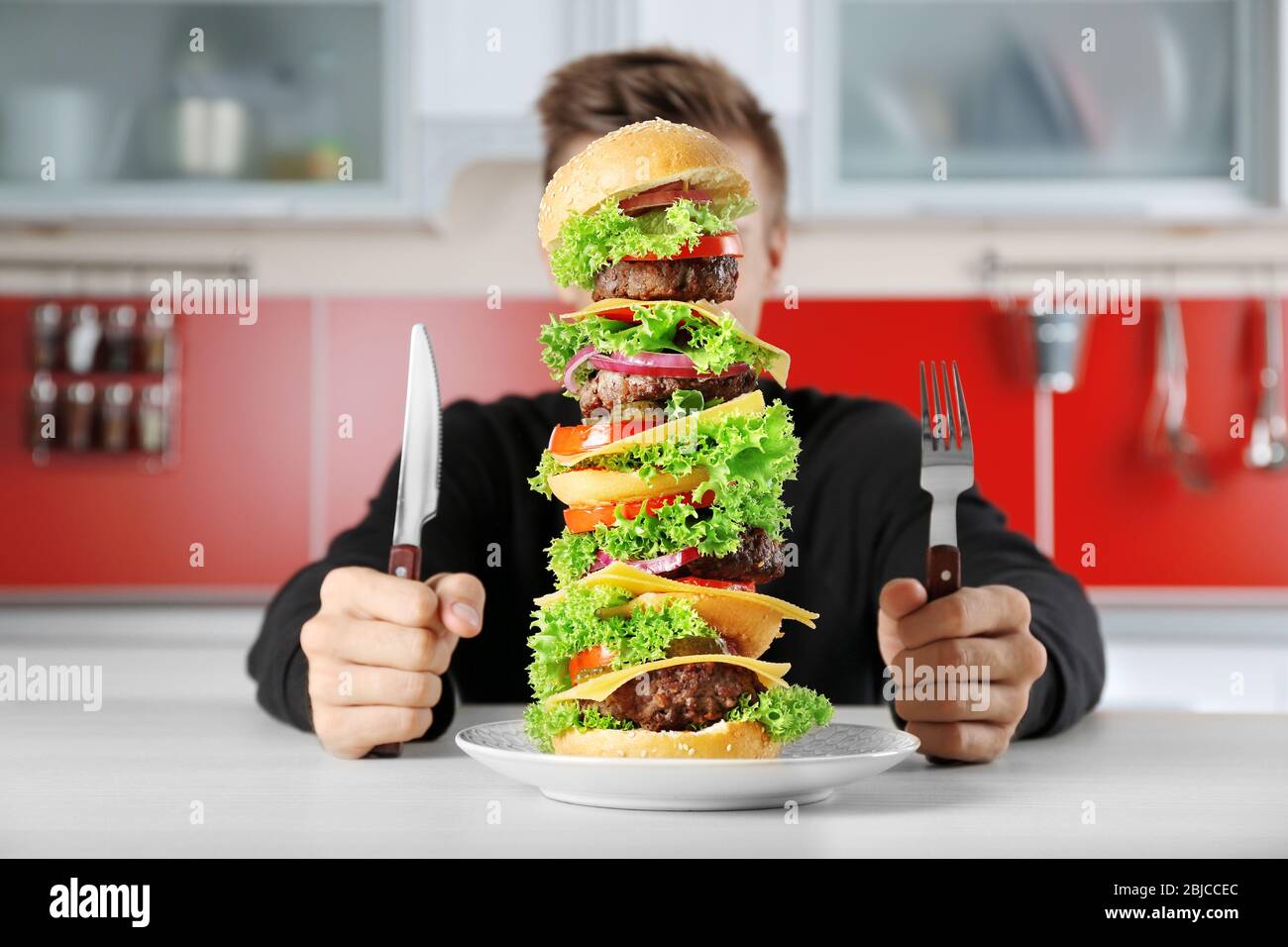 Man eating huge burger at table Stock Photo - Alamy