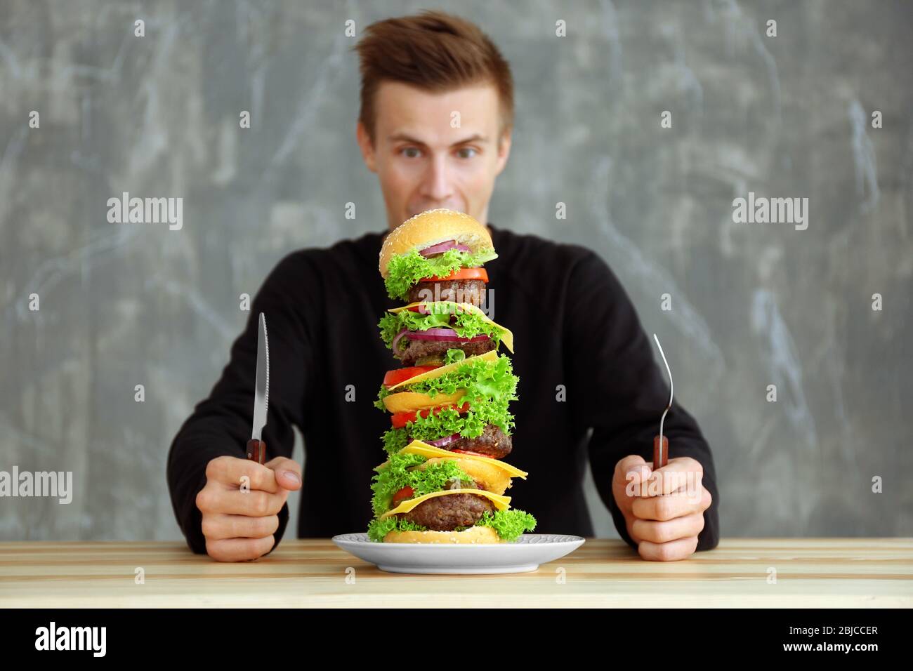 Man eating huge burger at table Stock Photo - Alamy