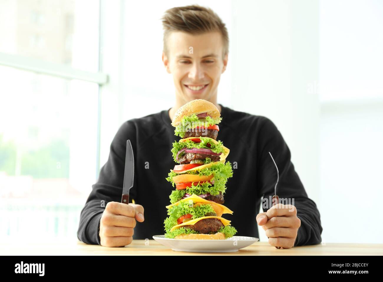 Man eating huge burger at table Stock Photo - Alamy
