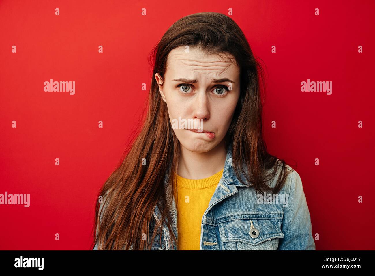 Studio shot of upset young woman purses lower lip, pouting and has ...