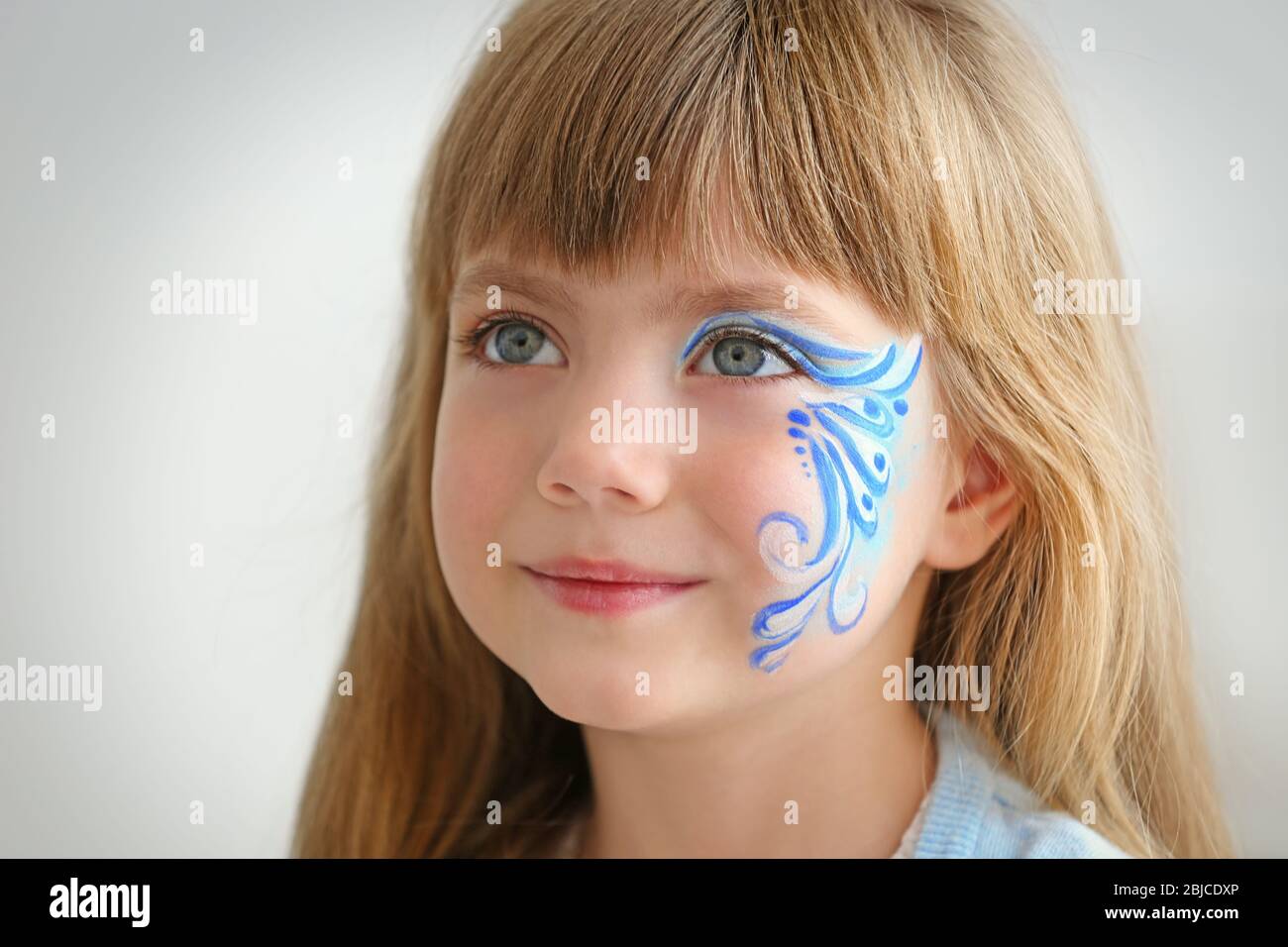Little girl with aqua makeup on light background Stock Photo - Alamy