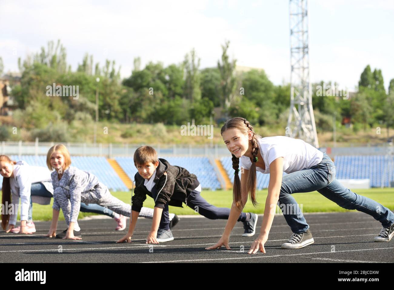 Cheerful children in ready position to run on track Stock Photo - Alamy