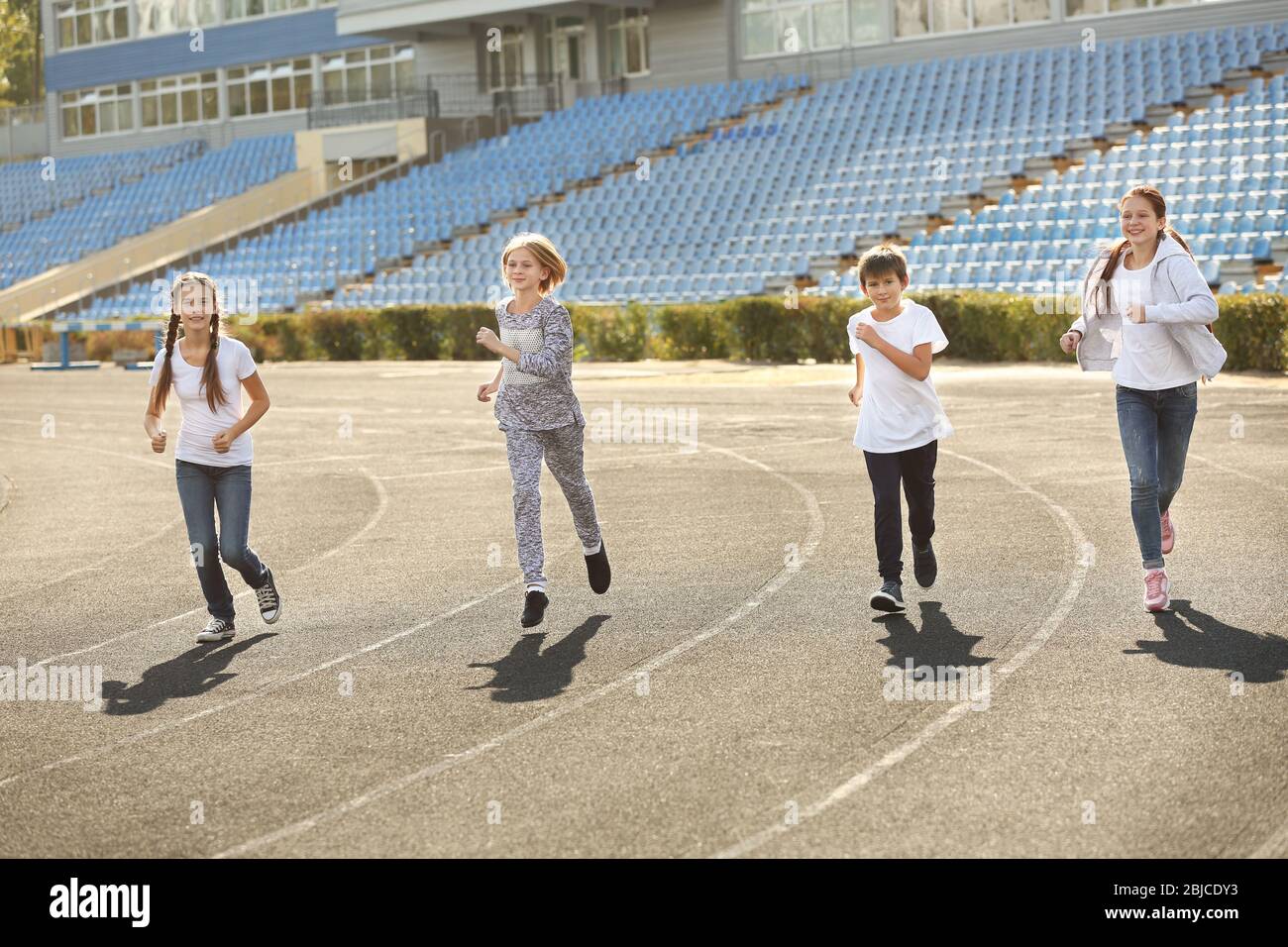 Sporty children running on track at stadium Stock Photo - Alamy