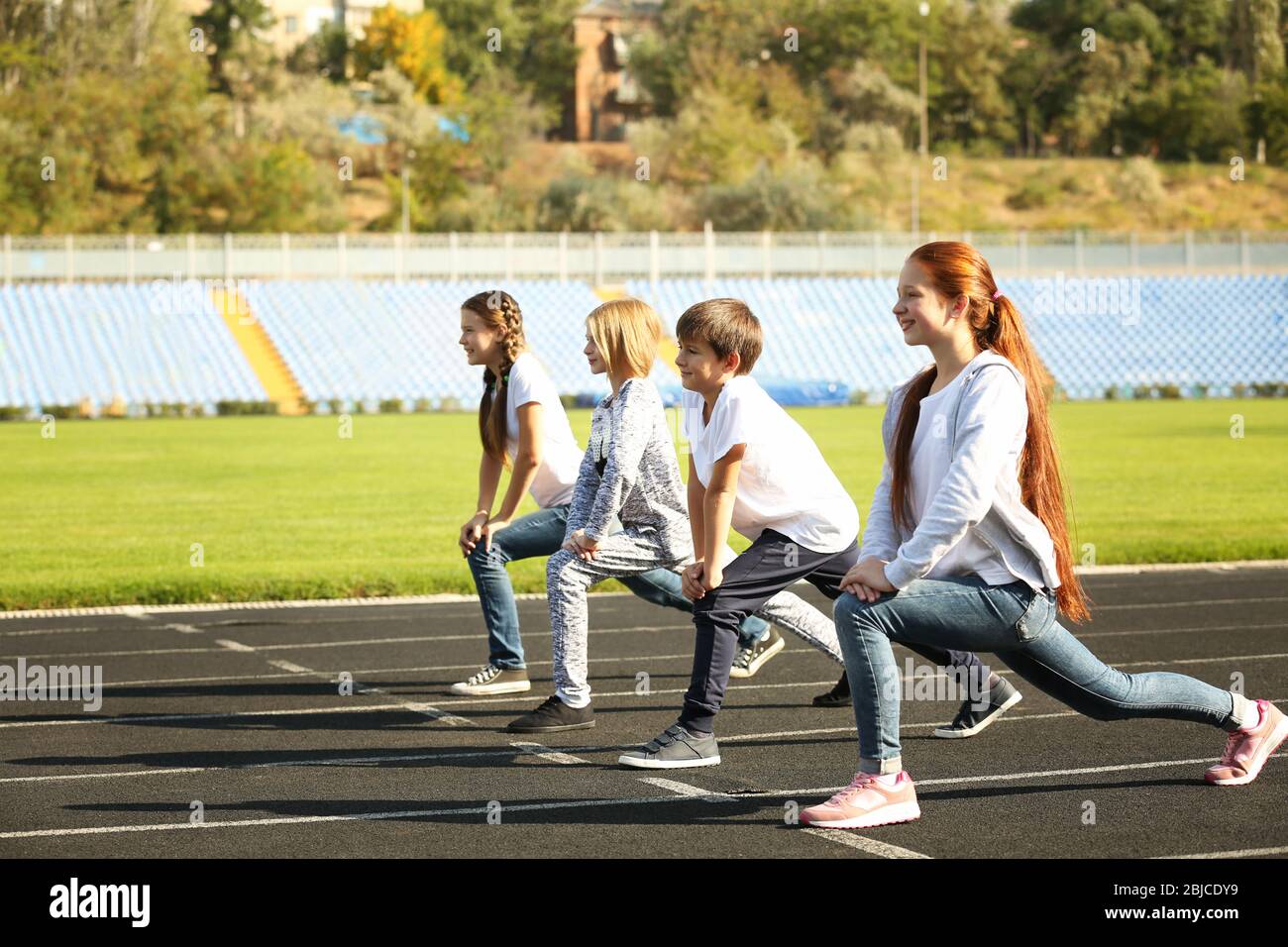 Cheerful children in ready position to run on track Stock Photo - Alamy