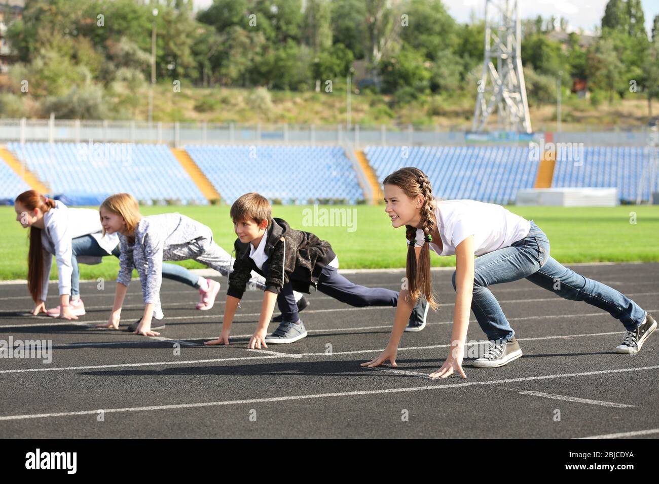 Cheerful children in ready position to run on track Stock Photo - Alamy