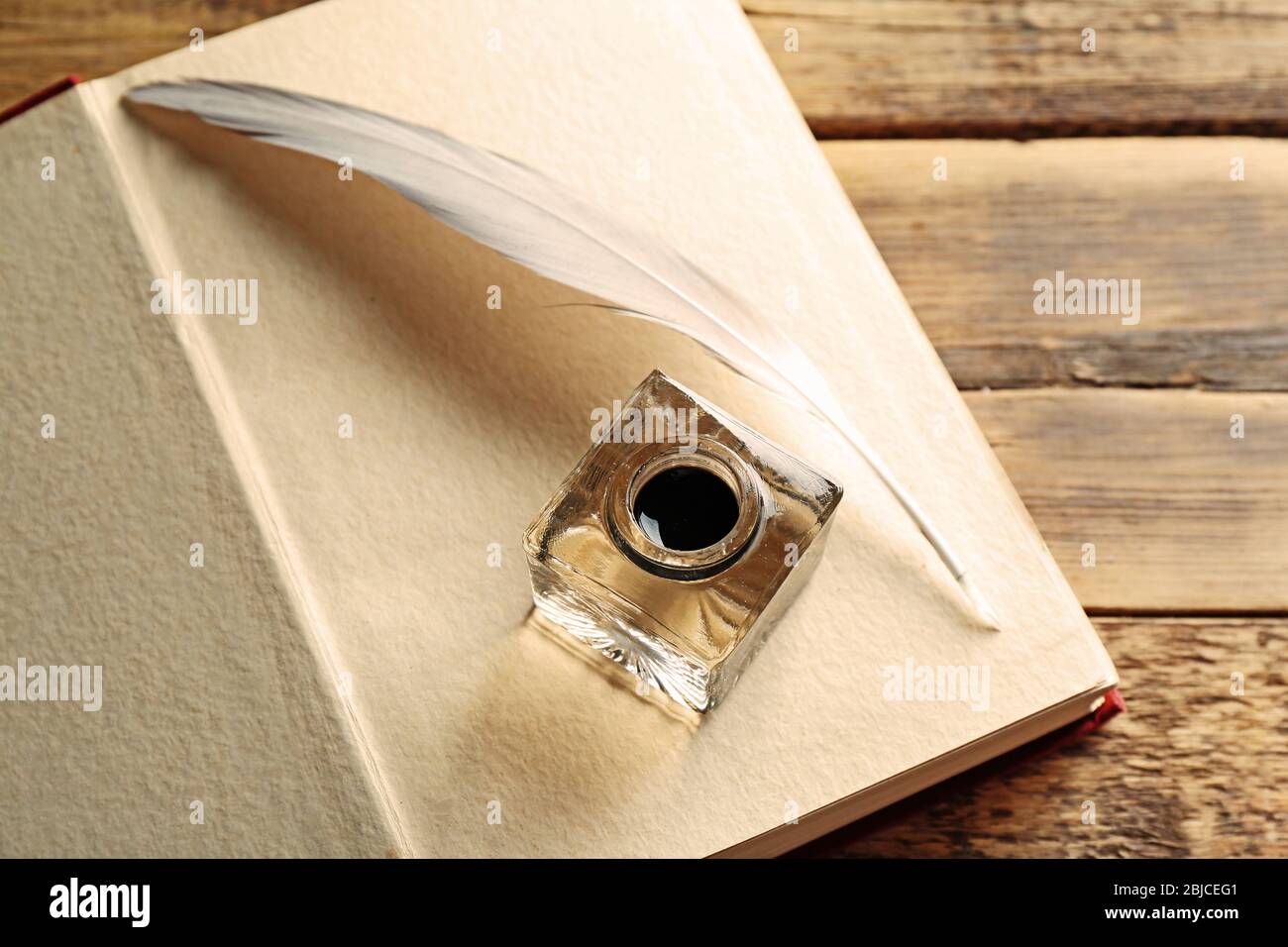Feather pen with inkwell and open notebook on wooden background Stock ...