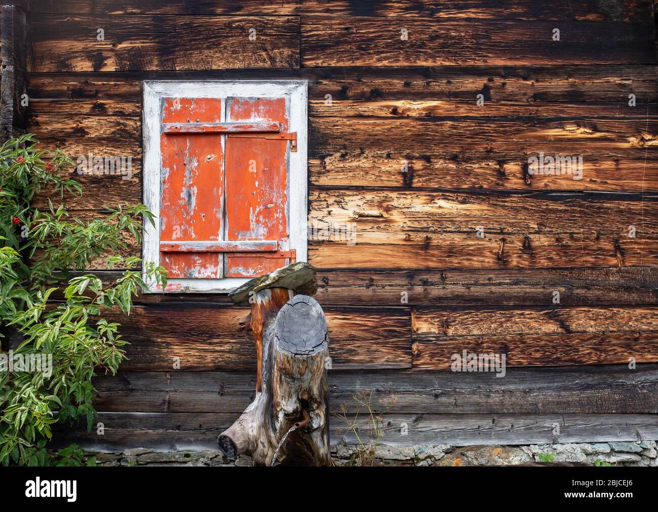 Closed window with vintage orange shutters on an old Swiss farm house ...