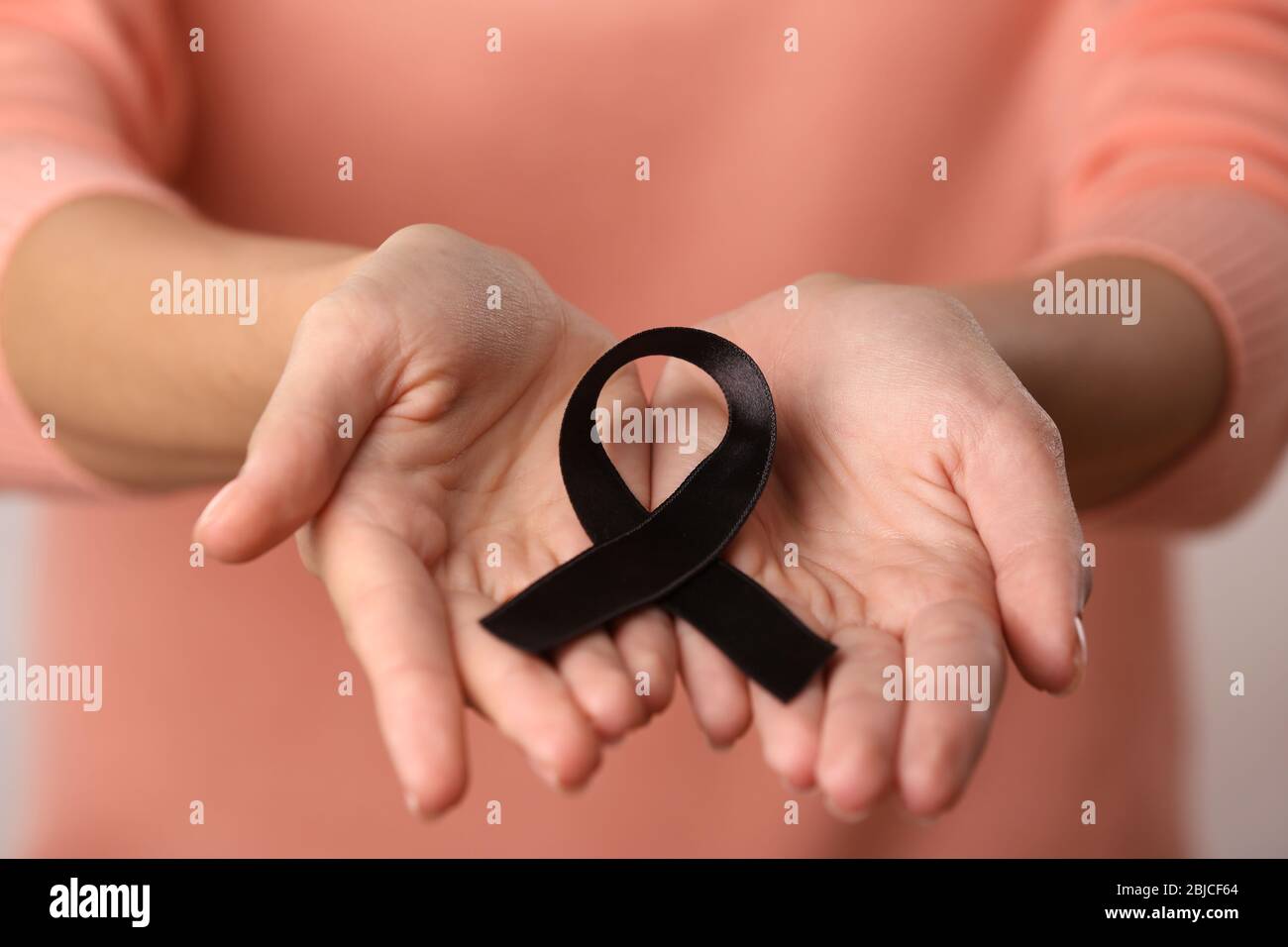 Close up view of female hands holding black ribbon. Melanoma and ...