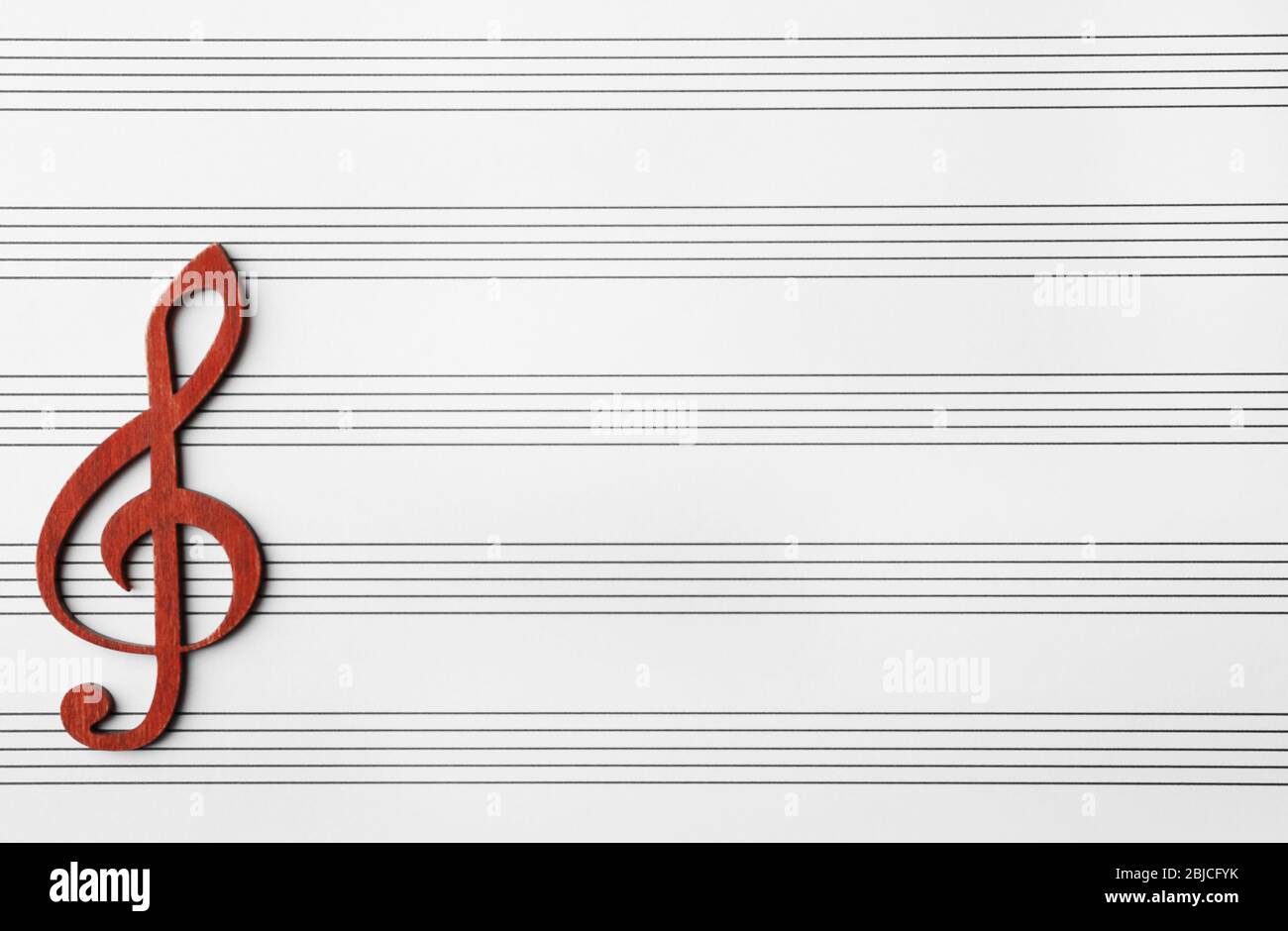 Wooden musical clef on music sheet background Stock Photo - Alamy