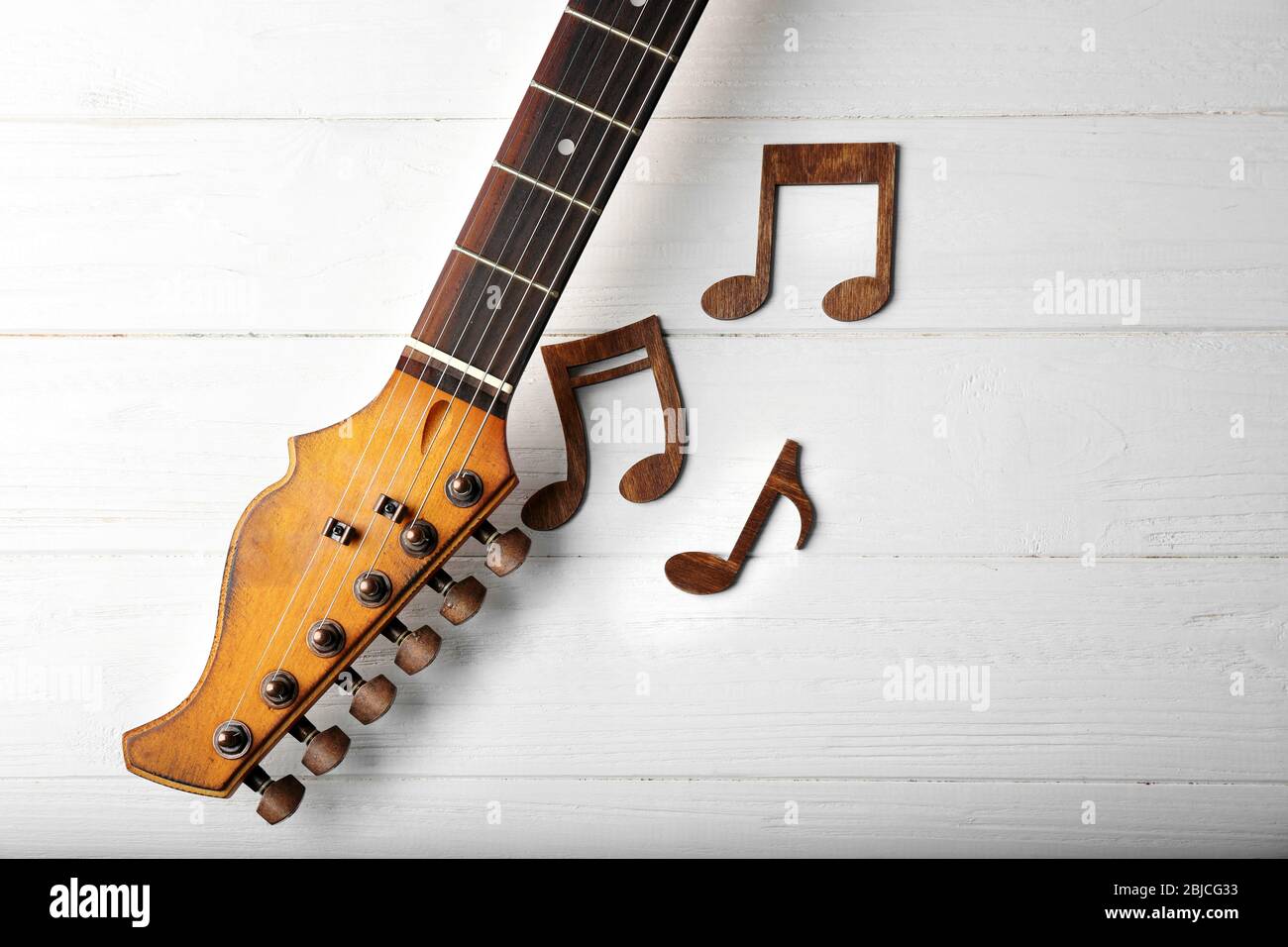 Musical notes and guitar neck on white wooden background Stock Photo ...