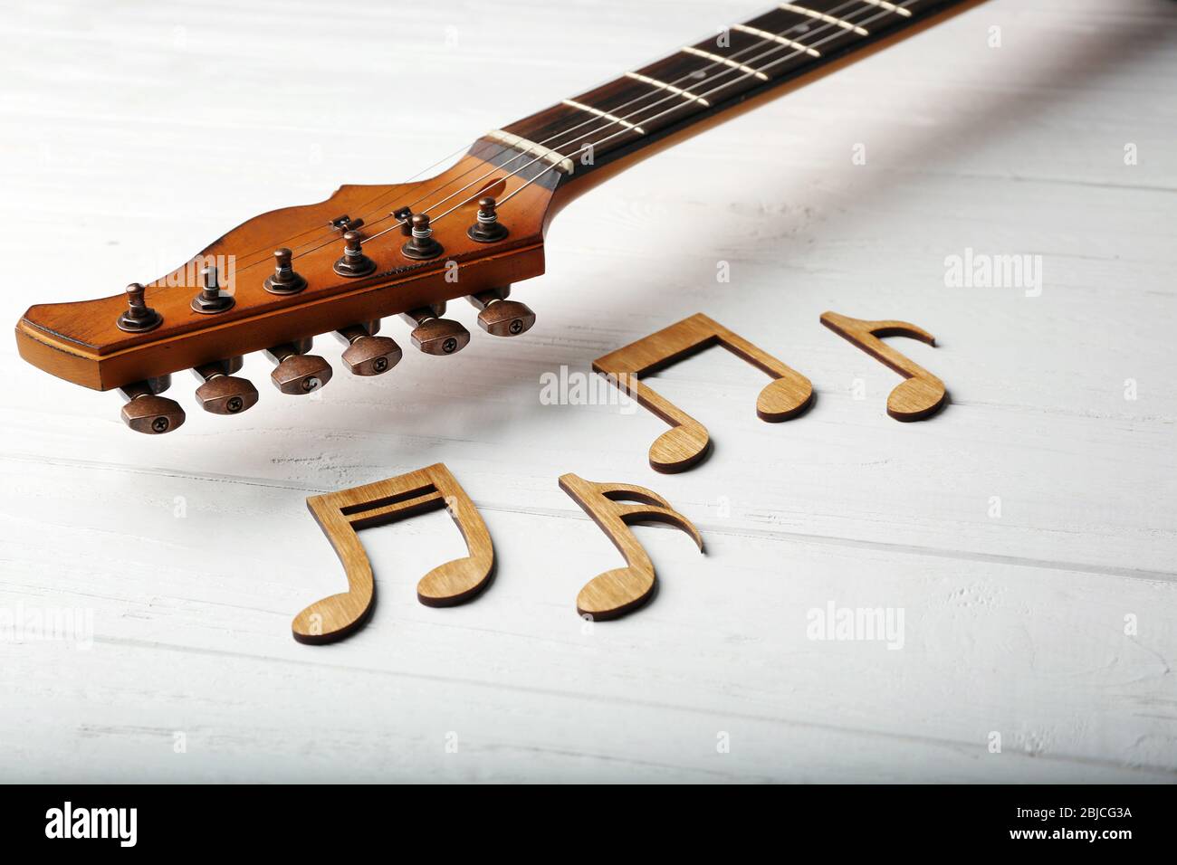 Musical notes and guitar neck on white wooden background Stock Photo ...