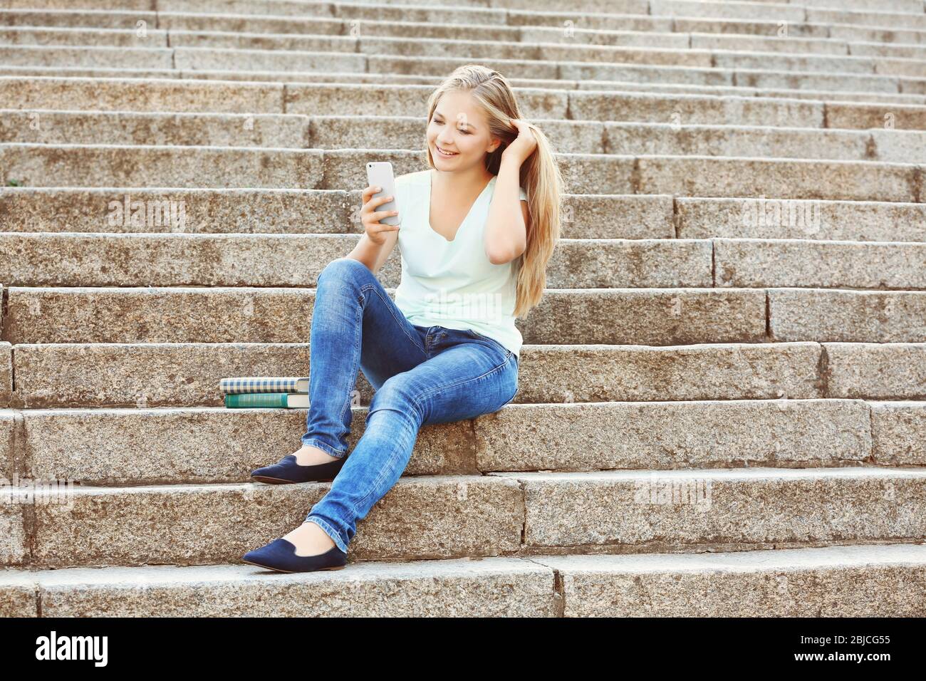Pretty teenager girl sitting on stairs with mobile phone Stock Photo ...
