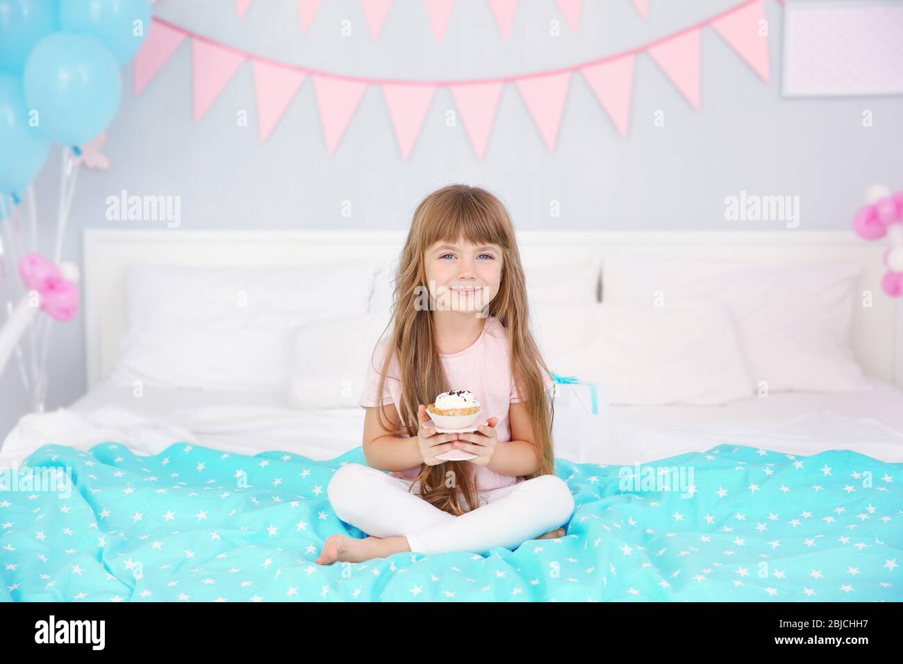 Cute birthday girl sitting on bed with tasty cake Stock Photo - Alamy