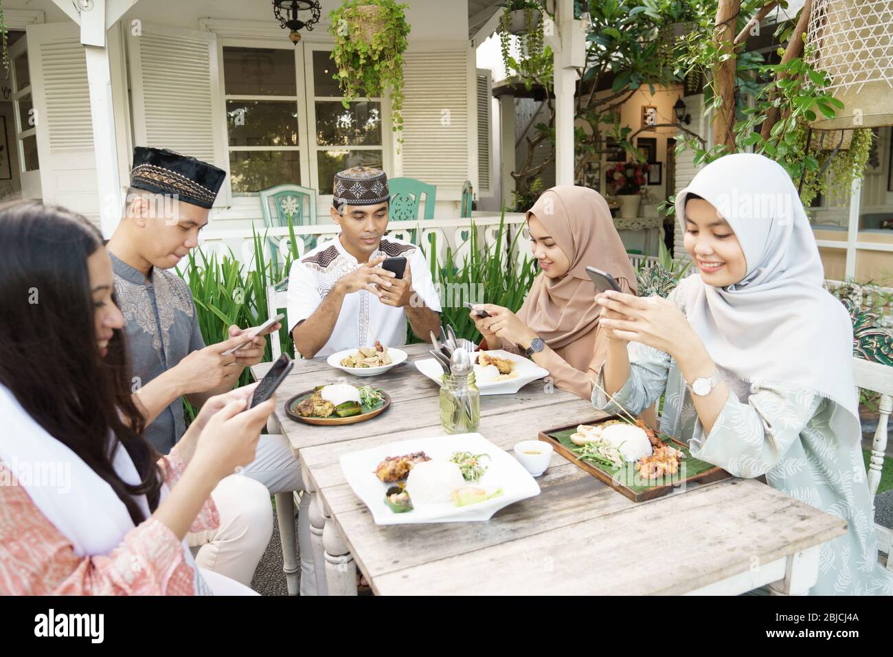 muslim people busy on their phone while gathering together with friend ...