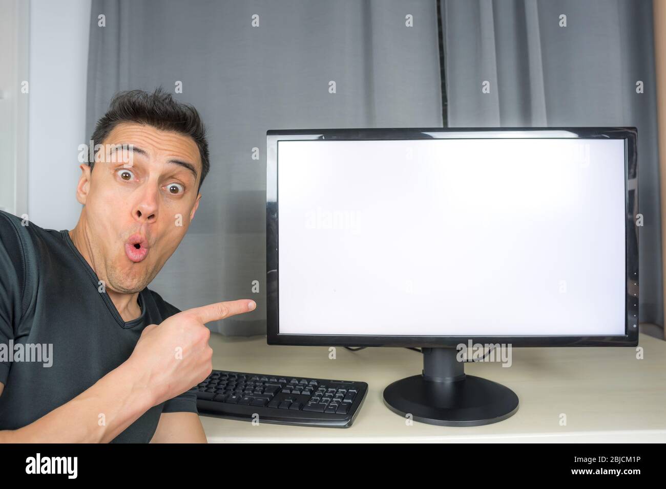 Surprised man in black shirt pointing at a computer screen (space copy ...