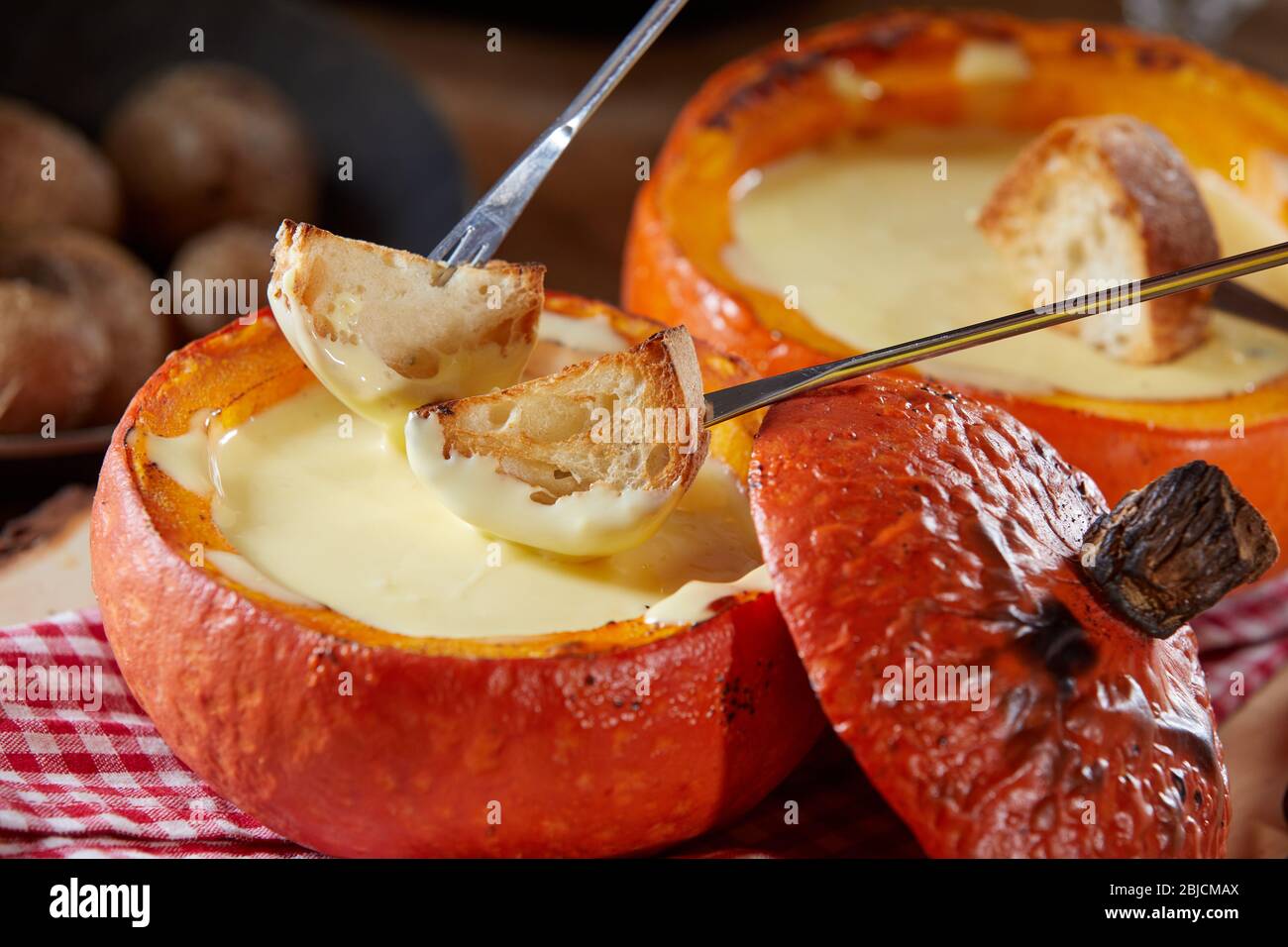 Traditional Swiss fondue with melted raclette cheese served in a hollow ...