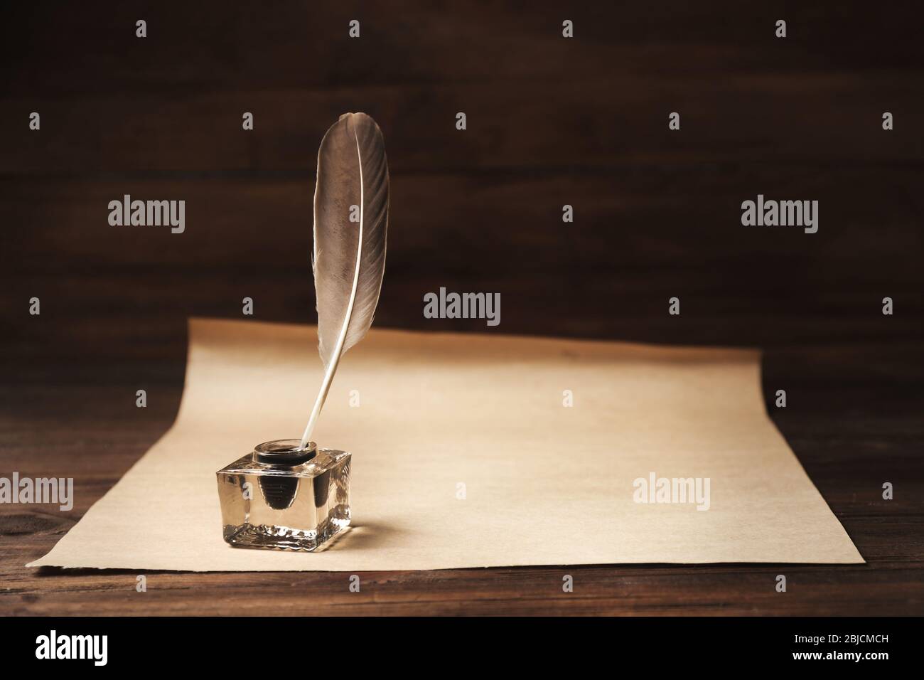Inkwell with feather and sheet of paper on wooden background Stock ...