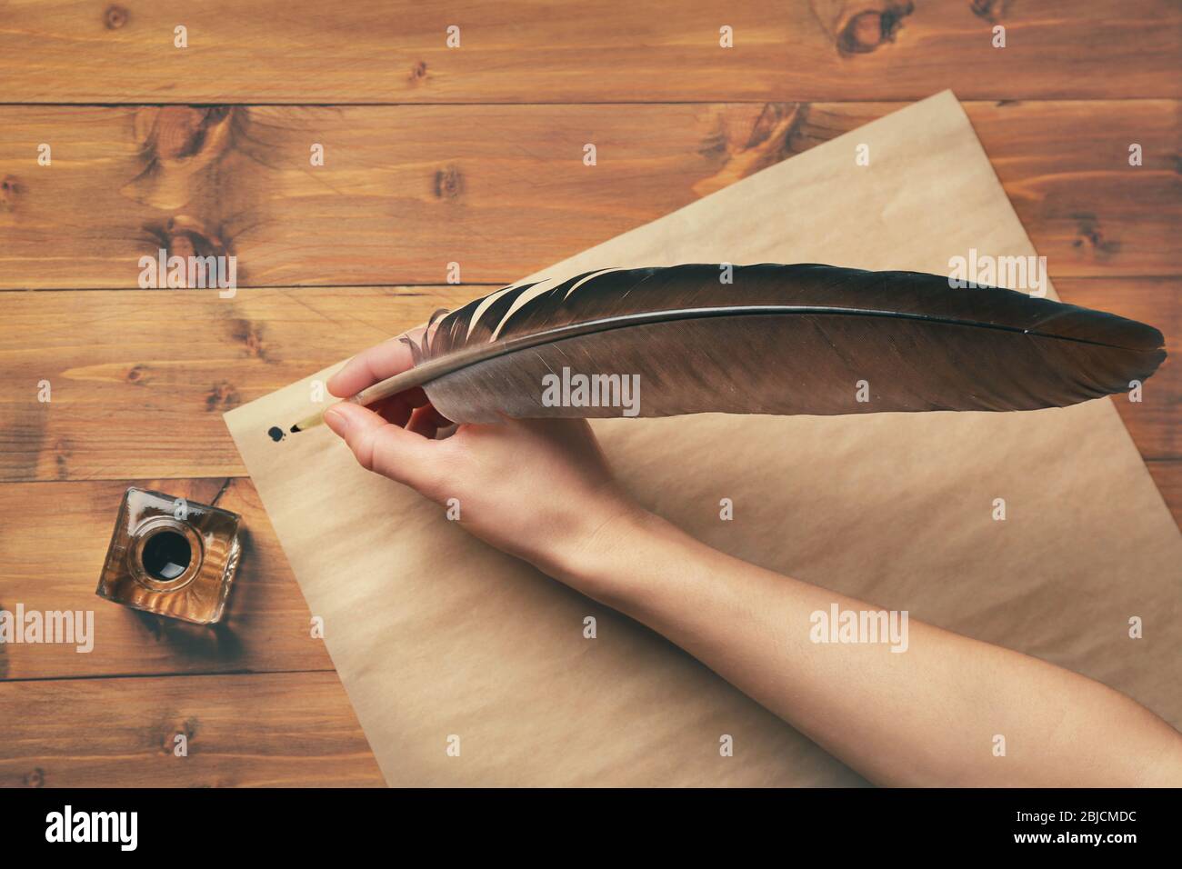 Female hand with feather writing on sheet of paper Stock Photo - Alamy