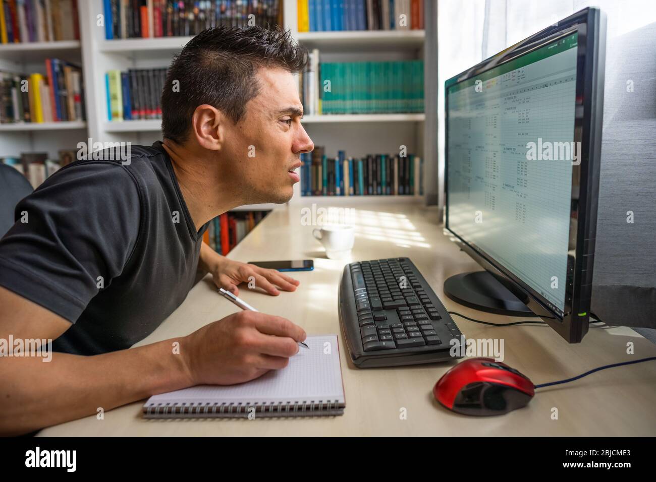 Man sitting in front of the computer in a shirt showing concern and ...