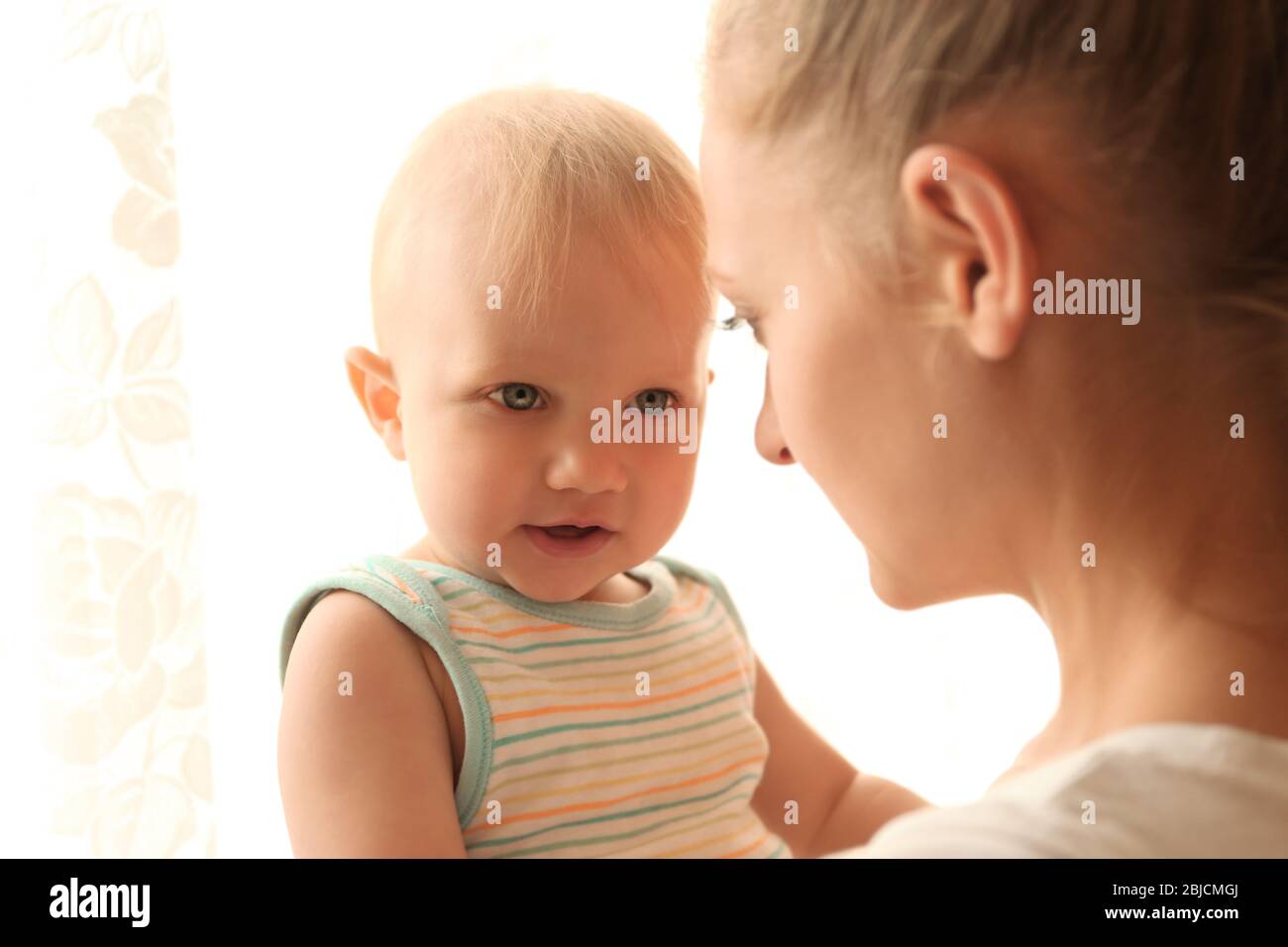 Happy mother and little baby boy on window background Stock Photo - Alamy