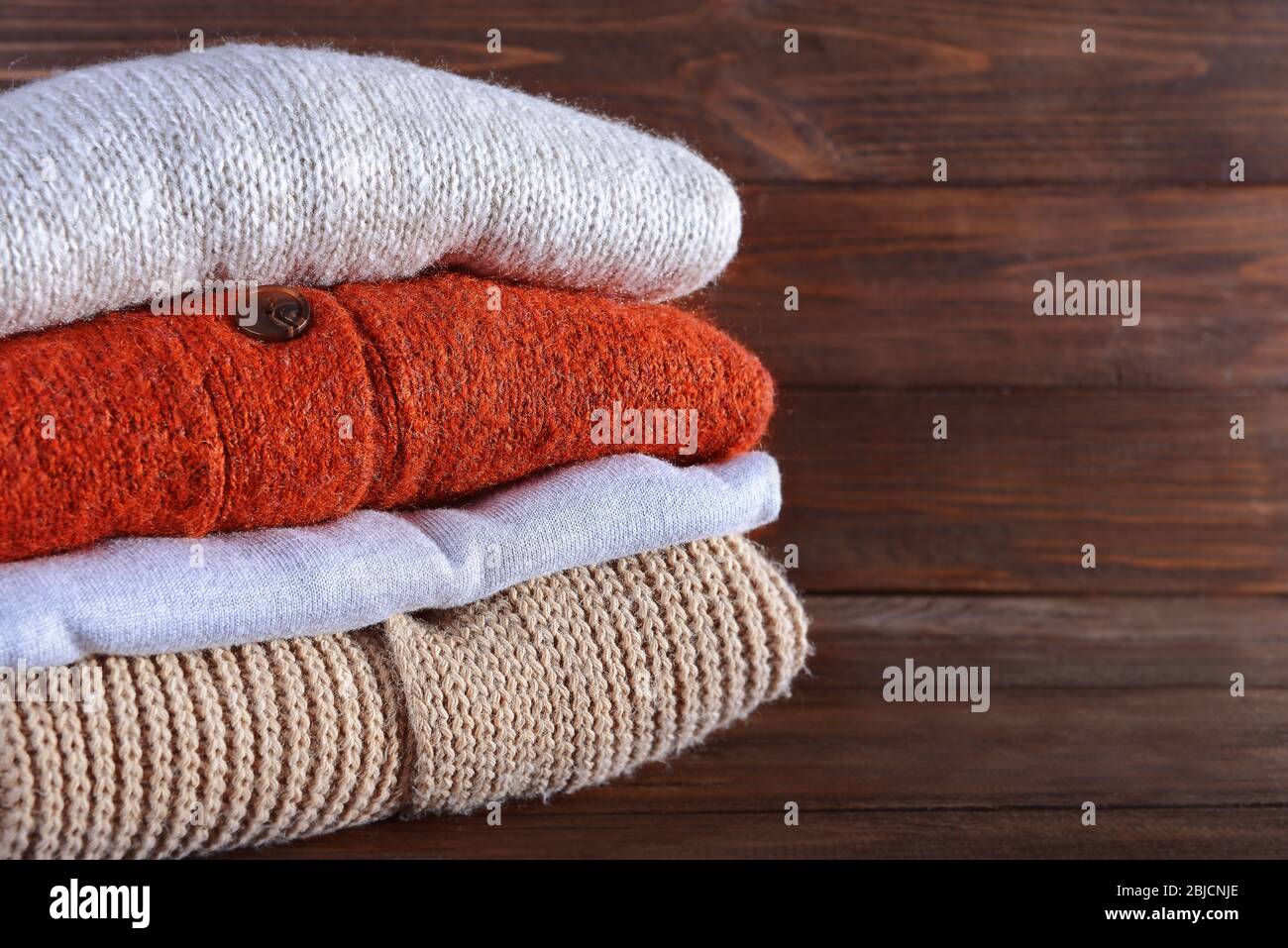 Stack of warm winter clothes on wooden background Stock Photo - Alamy