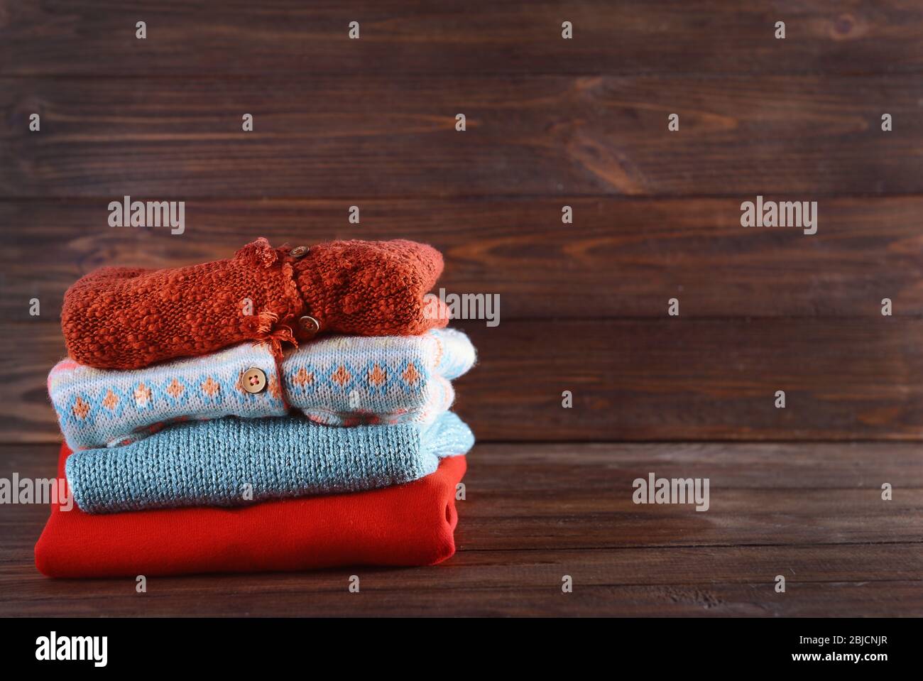Stack of warm winter clothes on wooden background Stock Photo - Alamy