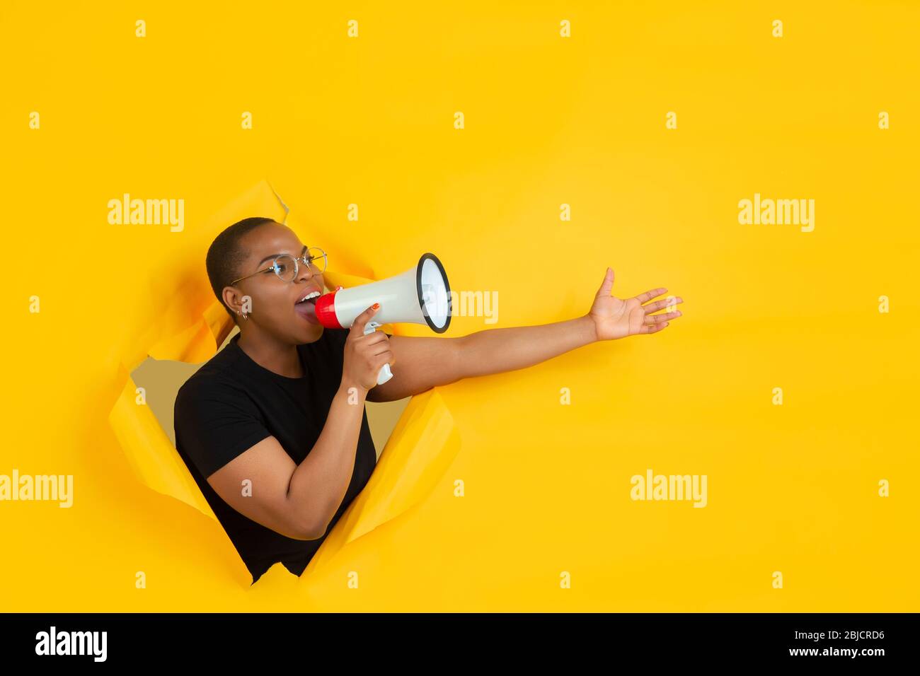 Shouting. Cheerful african-american young woman poses in torn yellow ...