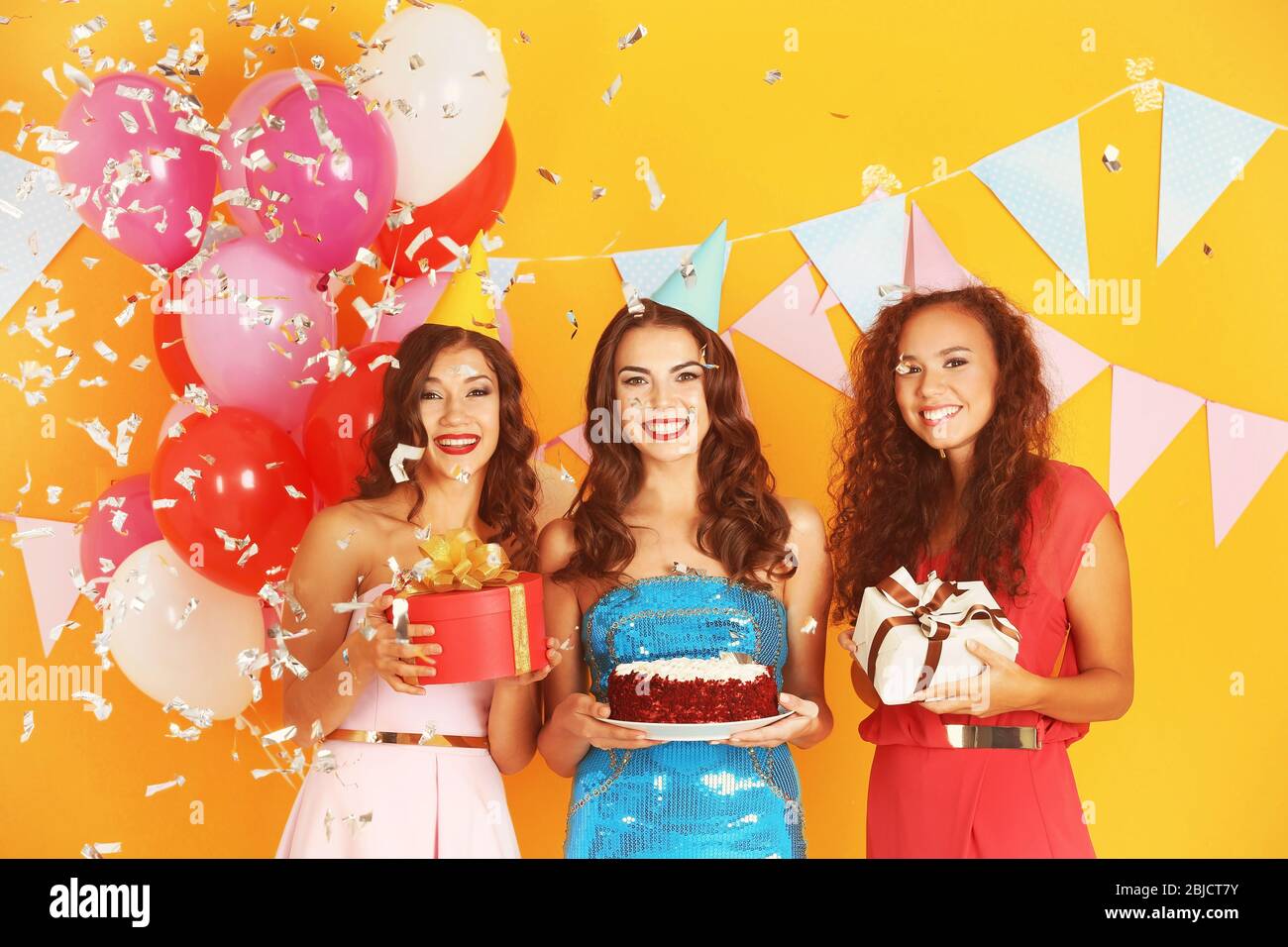 Beautiful young women at birthday party on yellow background Stock ...
