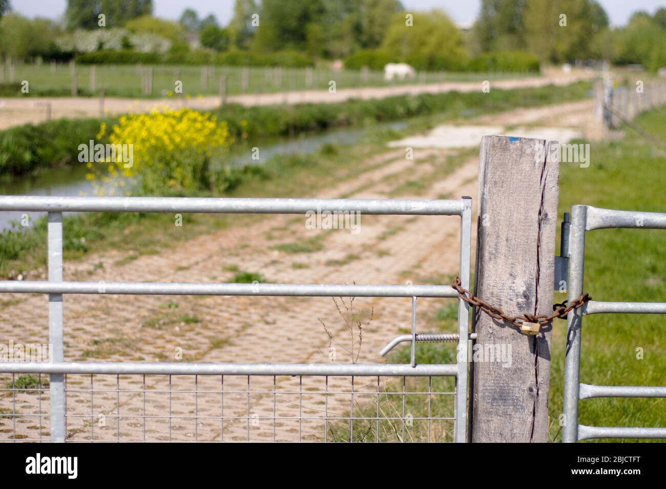 Detail of old steel closed gate that gives access to a path to a meadow ...