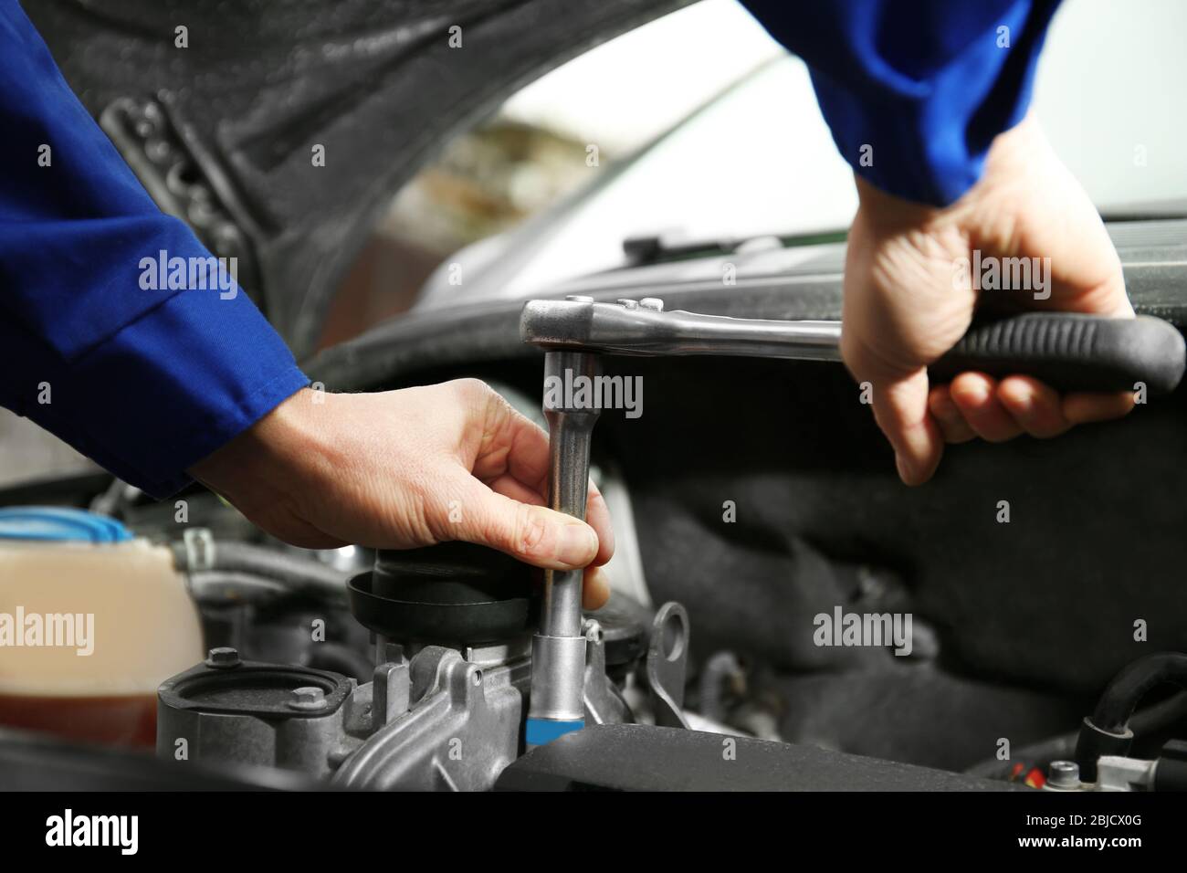 Mechanic repairing car with open hood Stock Photo - Alamy
