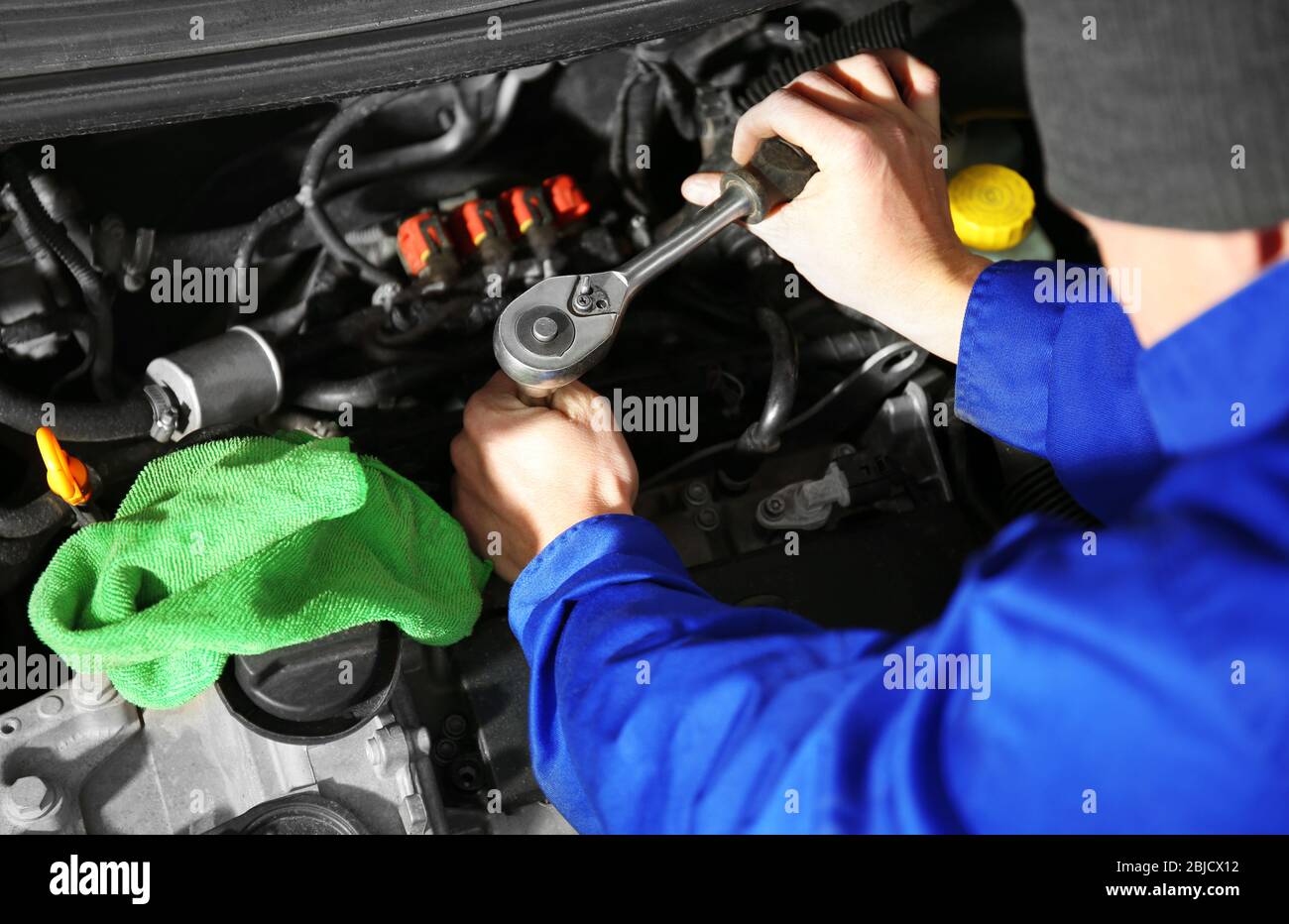 Mechanic repairing car with open hood Stock Photo - Alamy