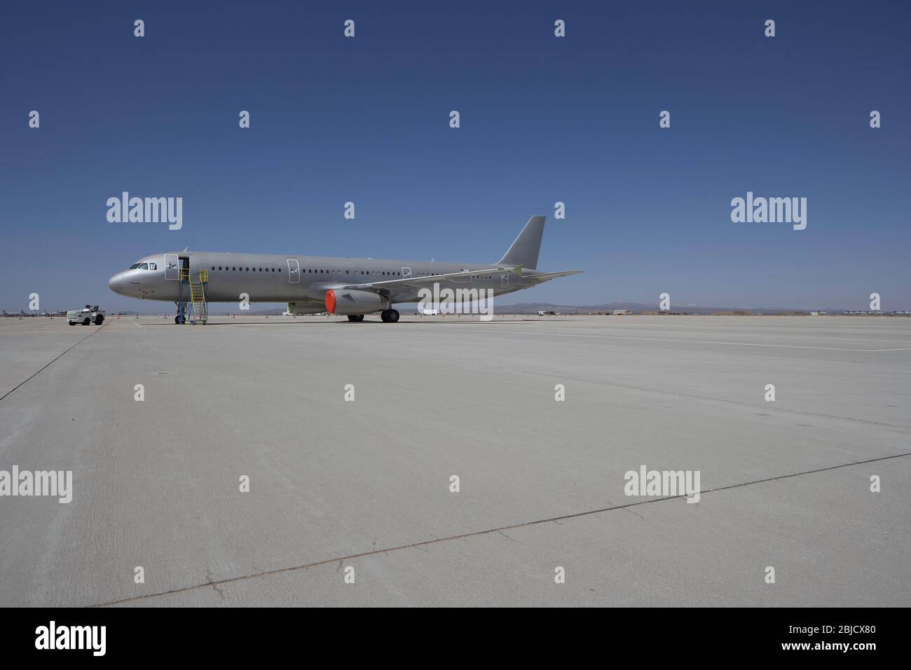 Silver passenger plane standing lonely on the airport with airstairs ...