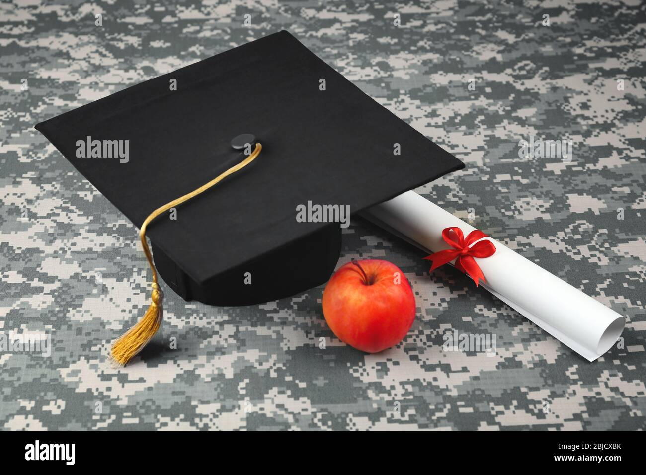 Graduation hat, diploma and apple on camouflage background Stock Photo ...