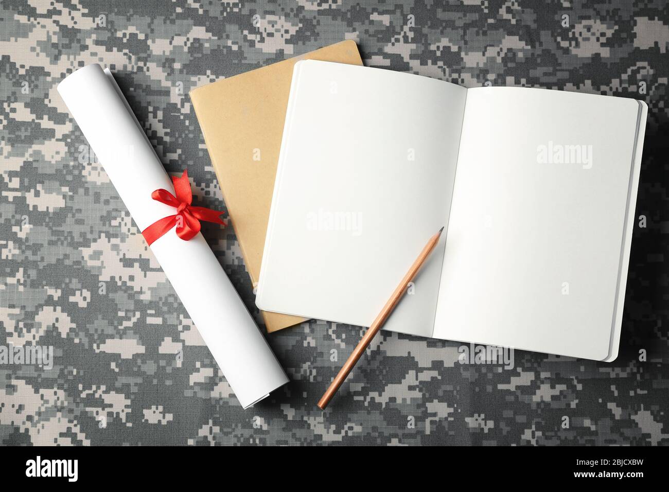 Diploma and book on camouflage background. Military education concept ...
