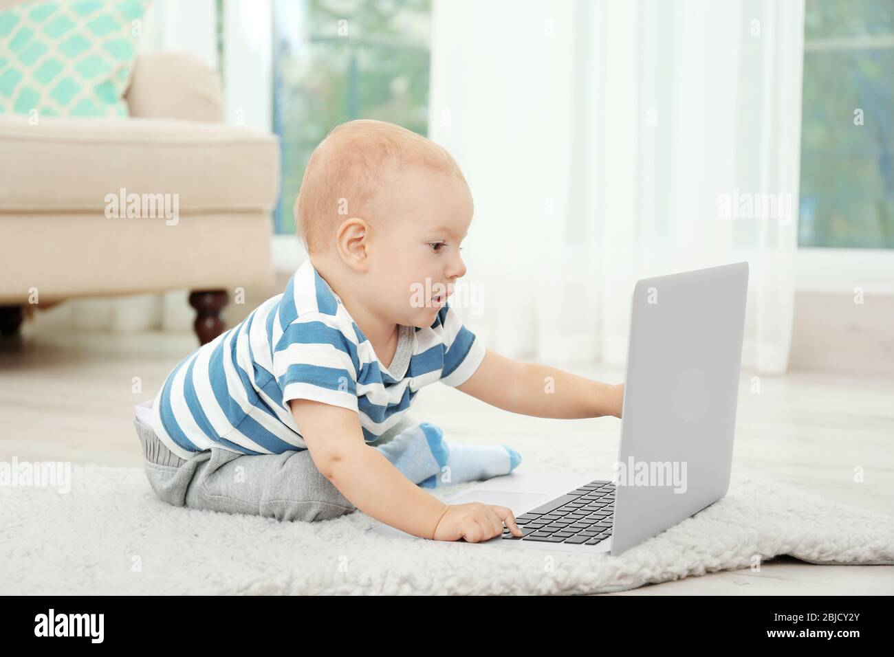 Cute baby boy with laptop on carpet Stock Photo - Alamy
