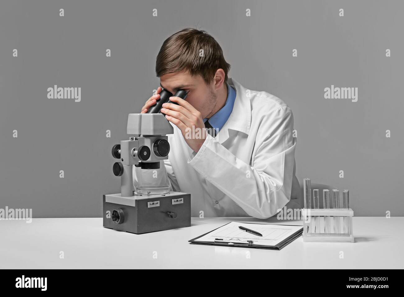 Young doctor working with microscope at table on light background Stock ...