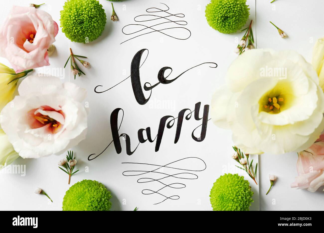 Quote "Be happy" written on paper with flowers on white background. Top ...