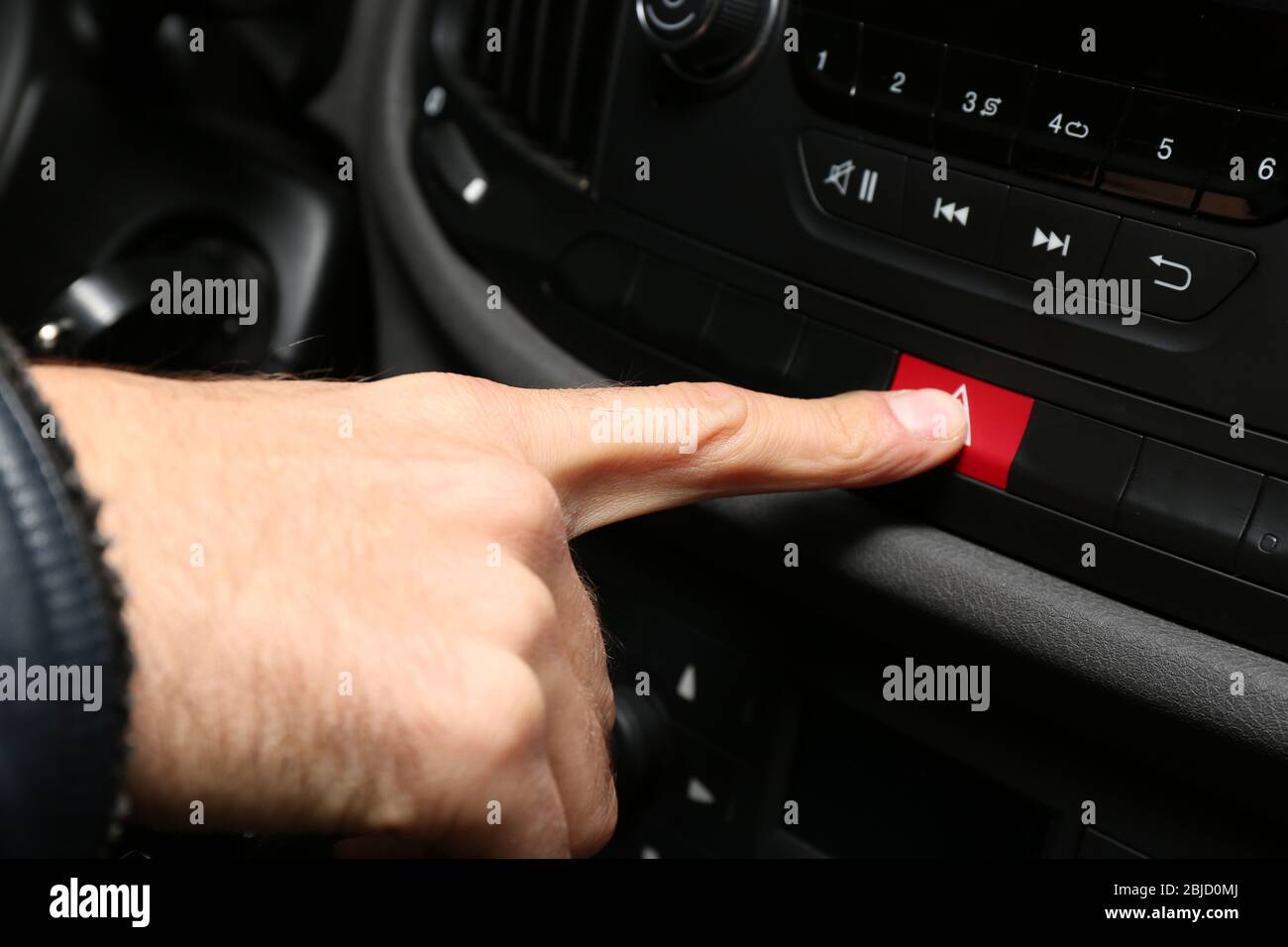 Male hand pressing emergency warning button on car console, closeup ...
