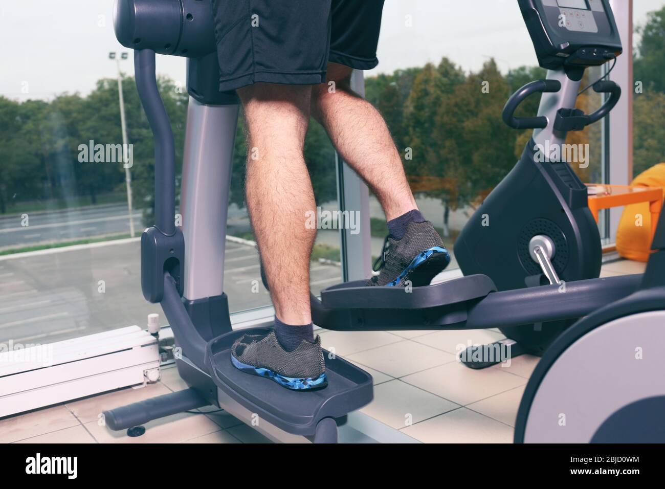 Man using elliptical trainer in gym Stock Photo - Alamy