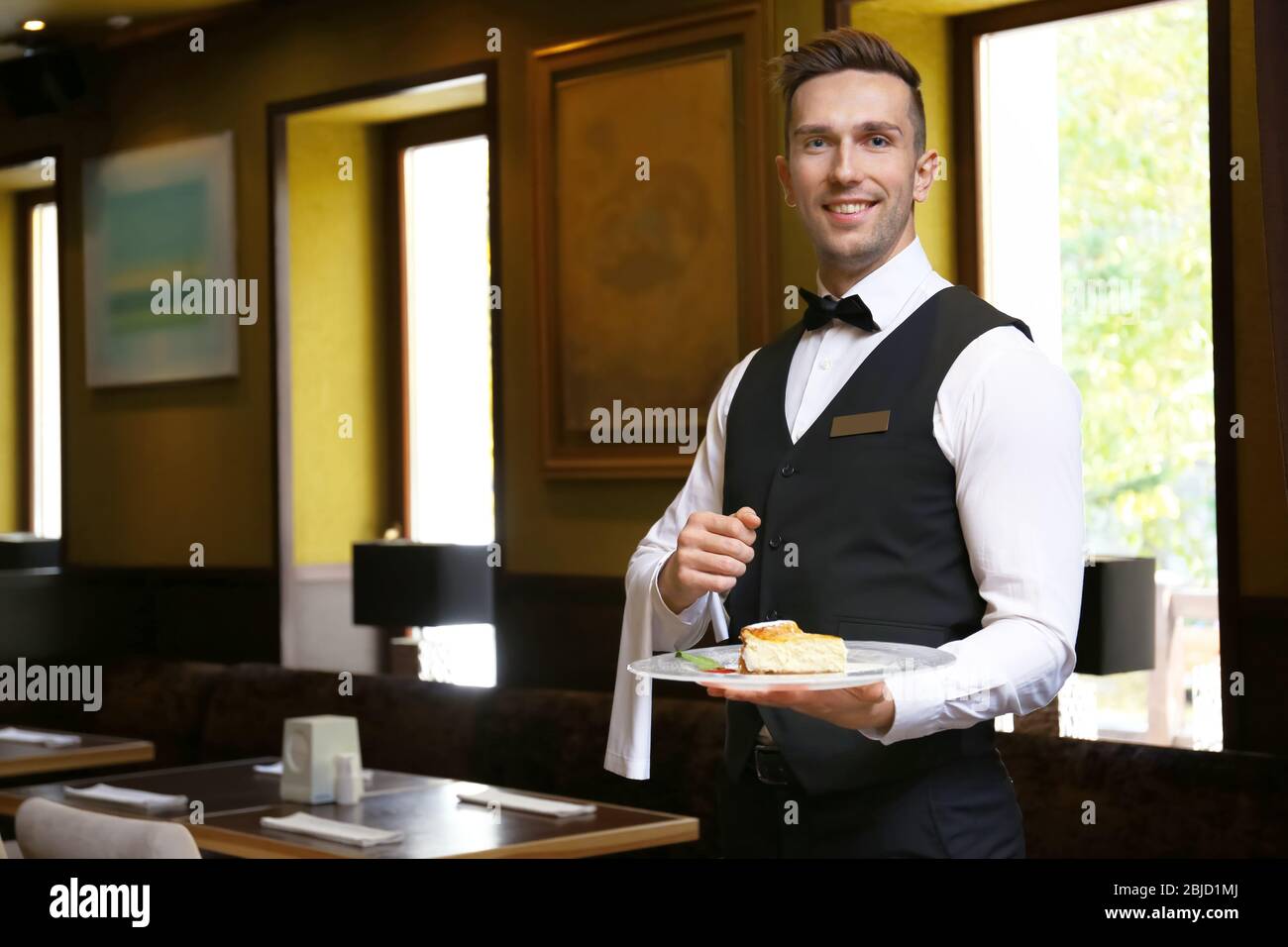 Handsome young waiter serving dessert at restaurant Stock Photo - Alamy